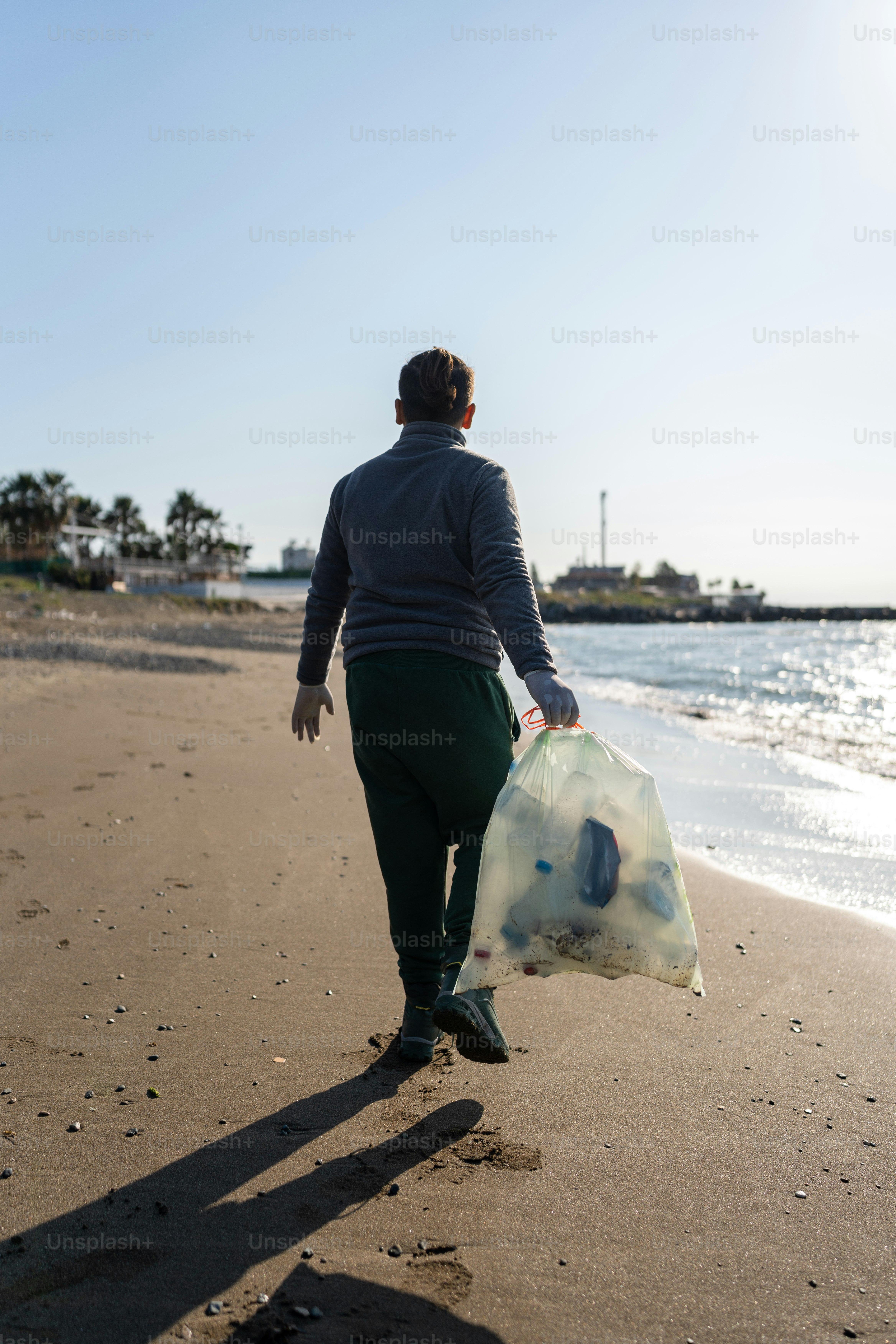 A man kneeling down on a beach next to the ocean photo – Clearing Image ...