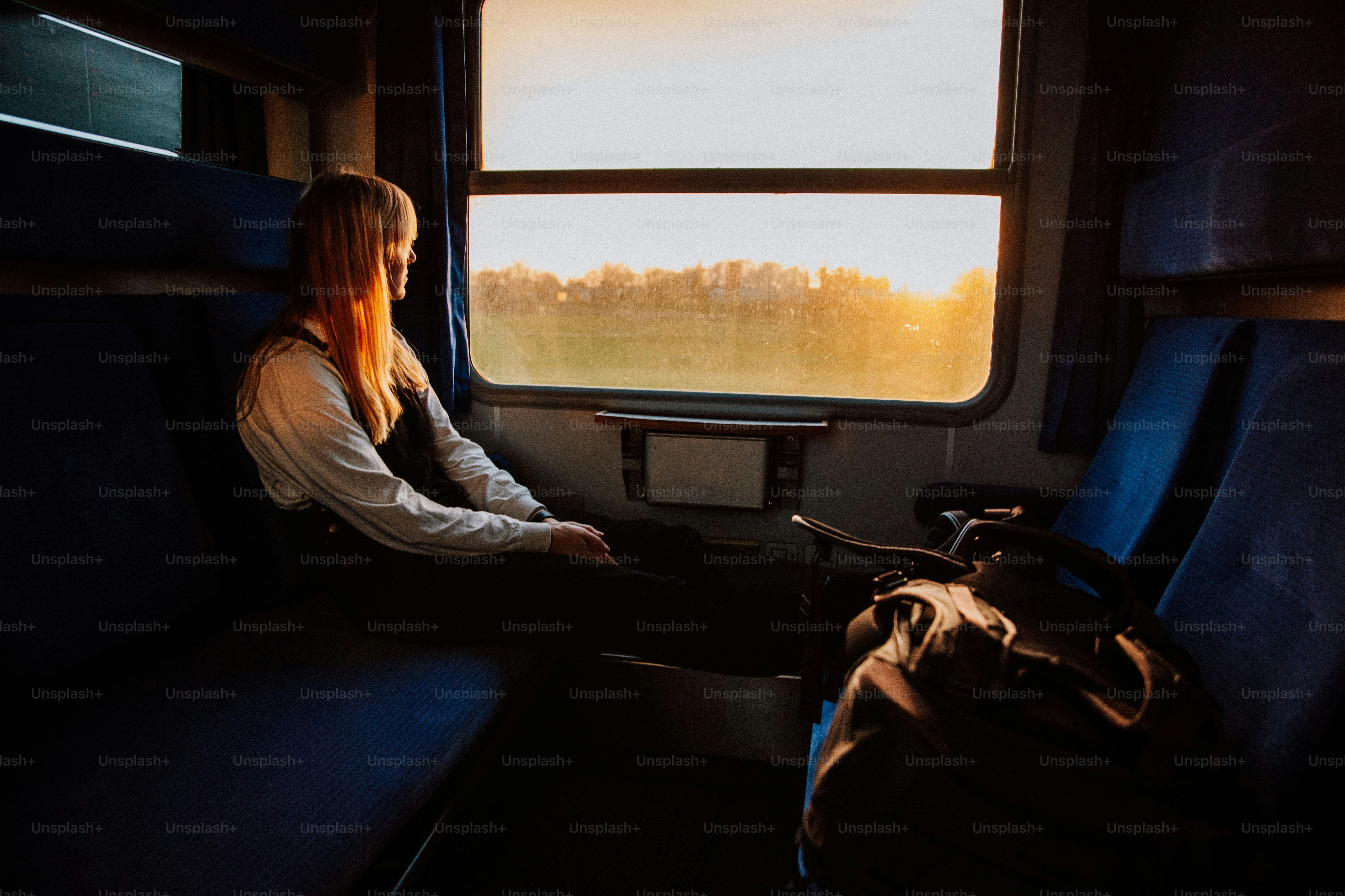 A woman sitting on a train looking out the window photo – Train travel ...