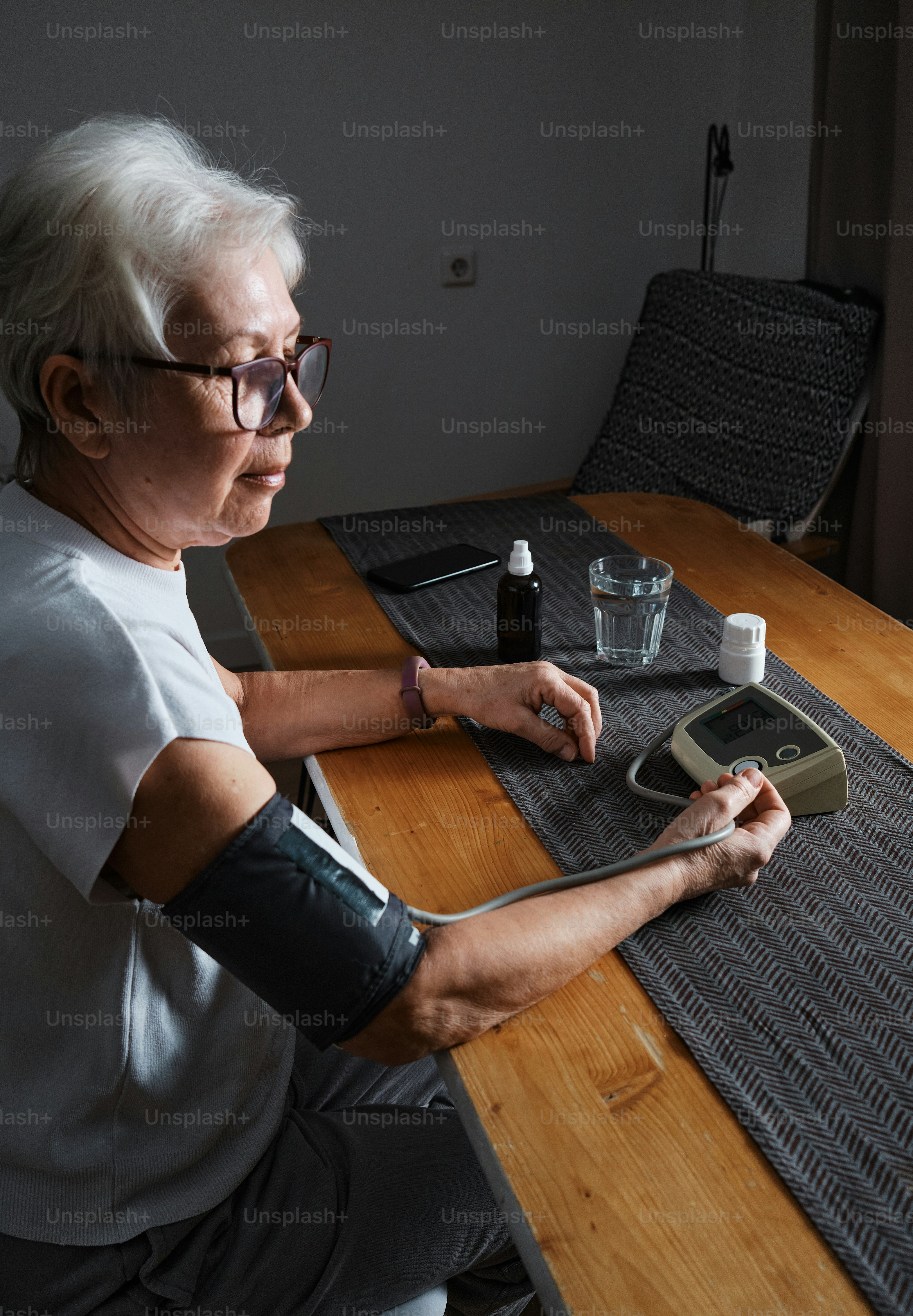 An older woman sitting on a couch blowing her nose photo – Patient ...