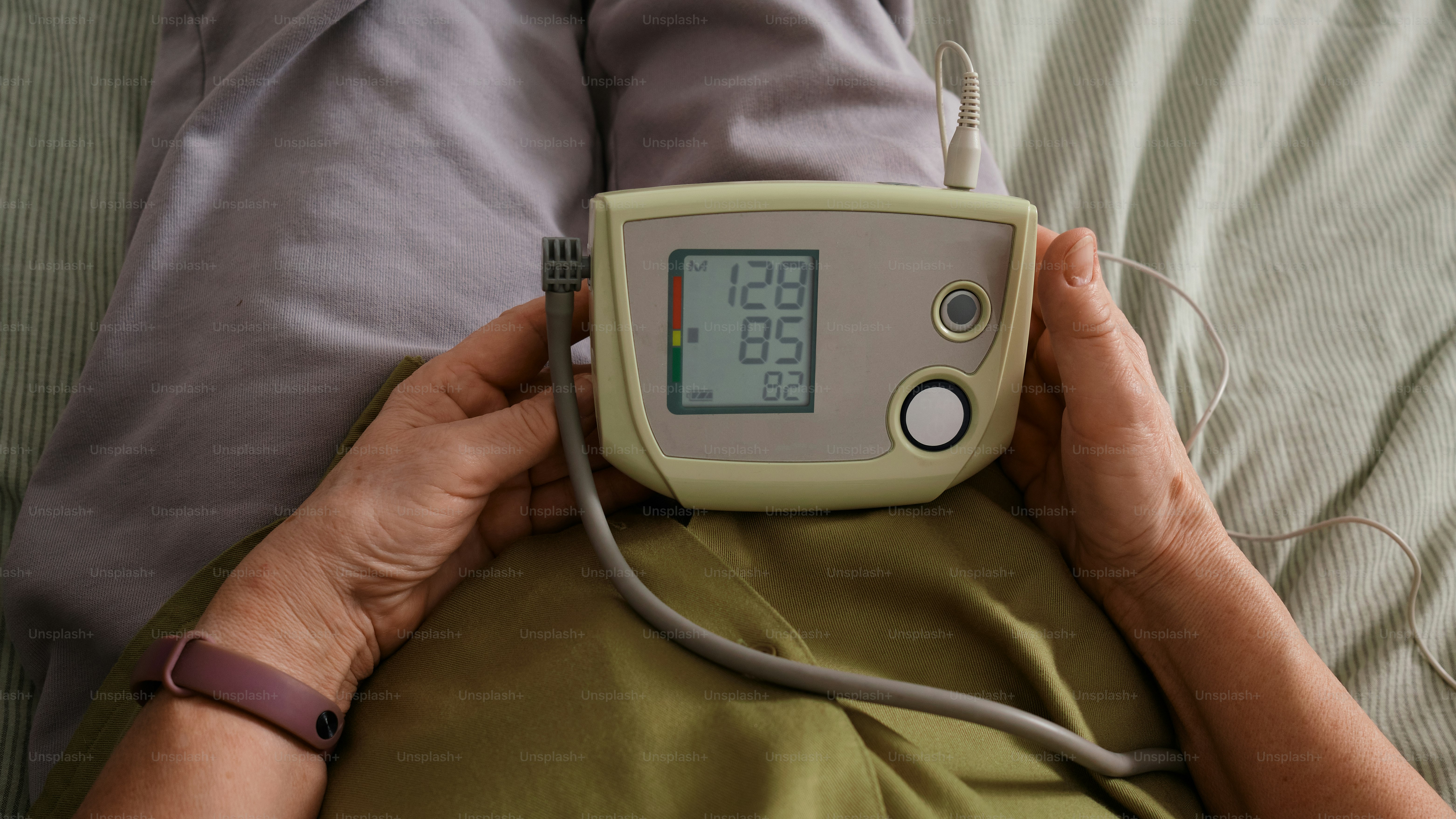 A person laying in a bed with a blood pressure meter photo – Medical ...