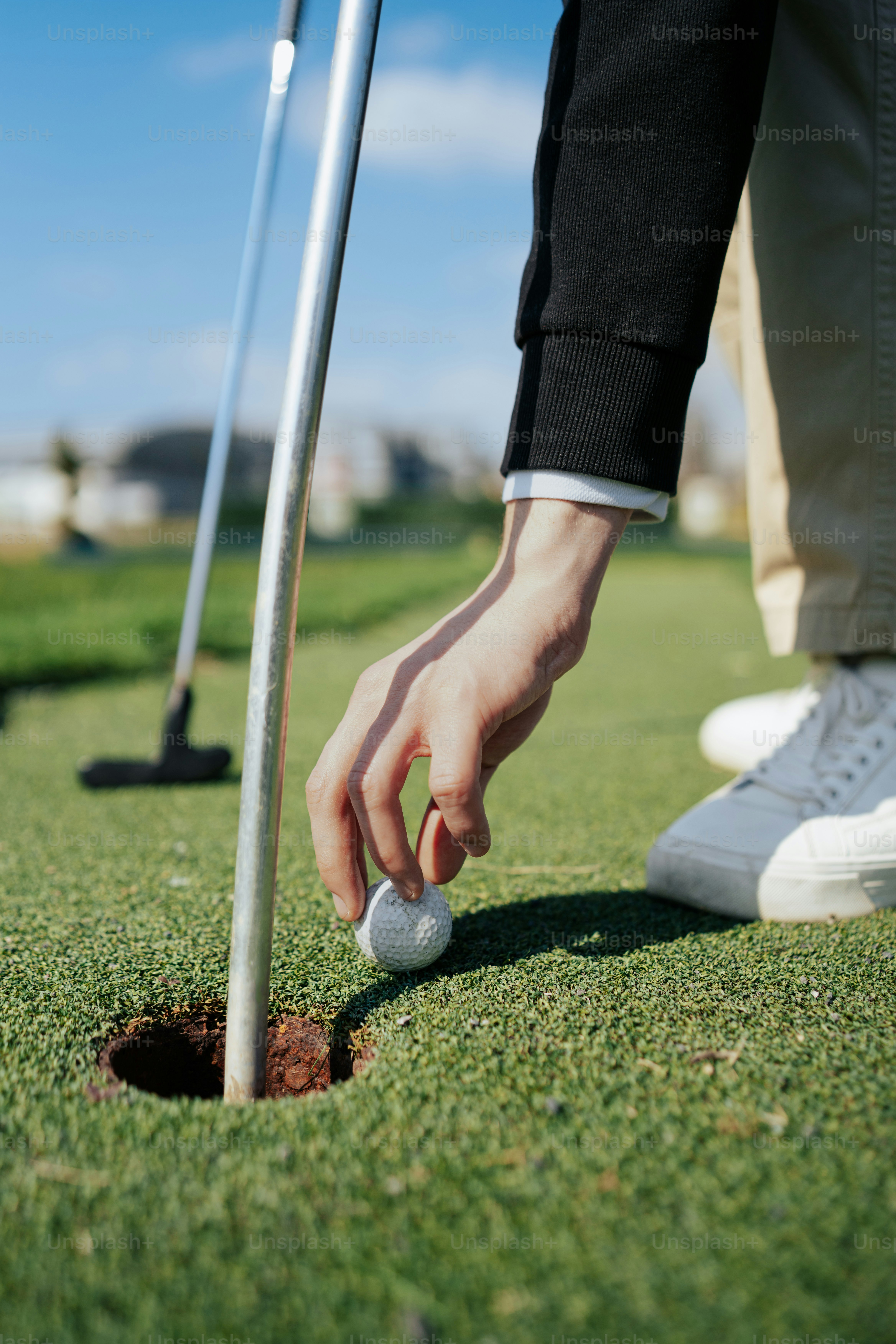 A person putting a golf ball into a hole photo – Green Image on Unsplash