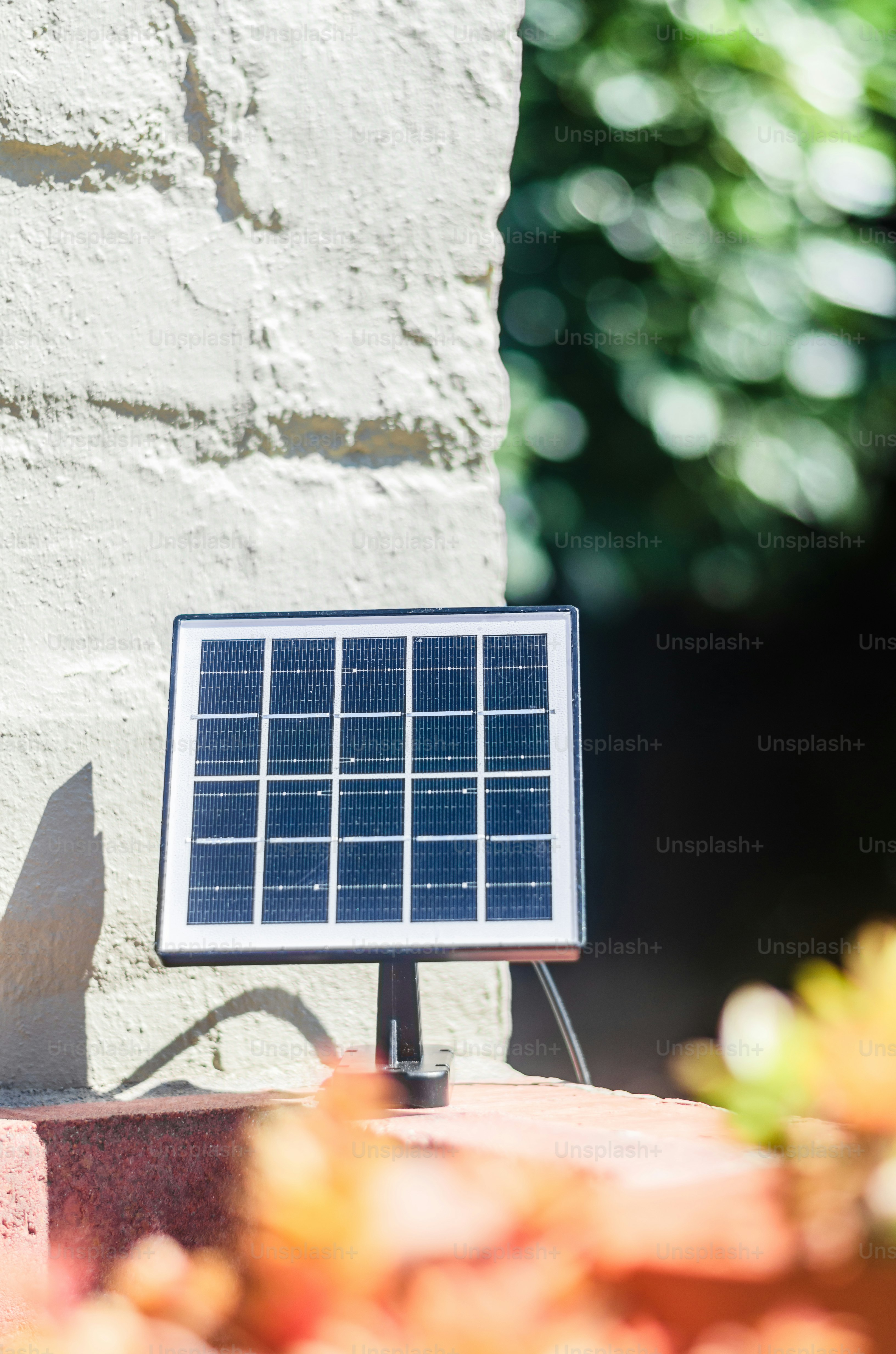 A small solar panel sitting on top of a brick wall photo – Renewable ...