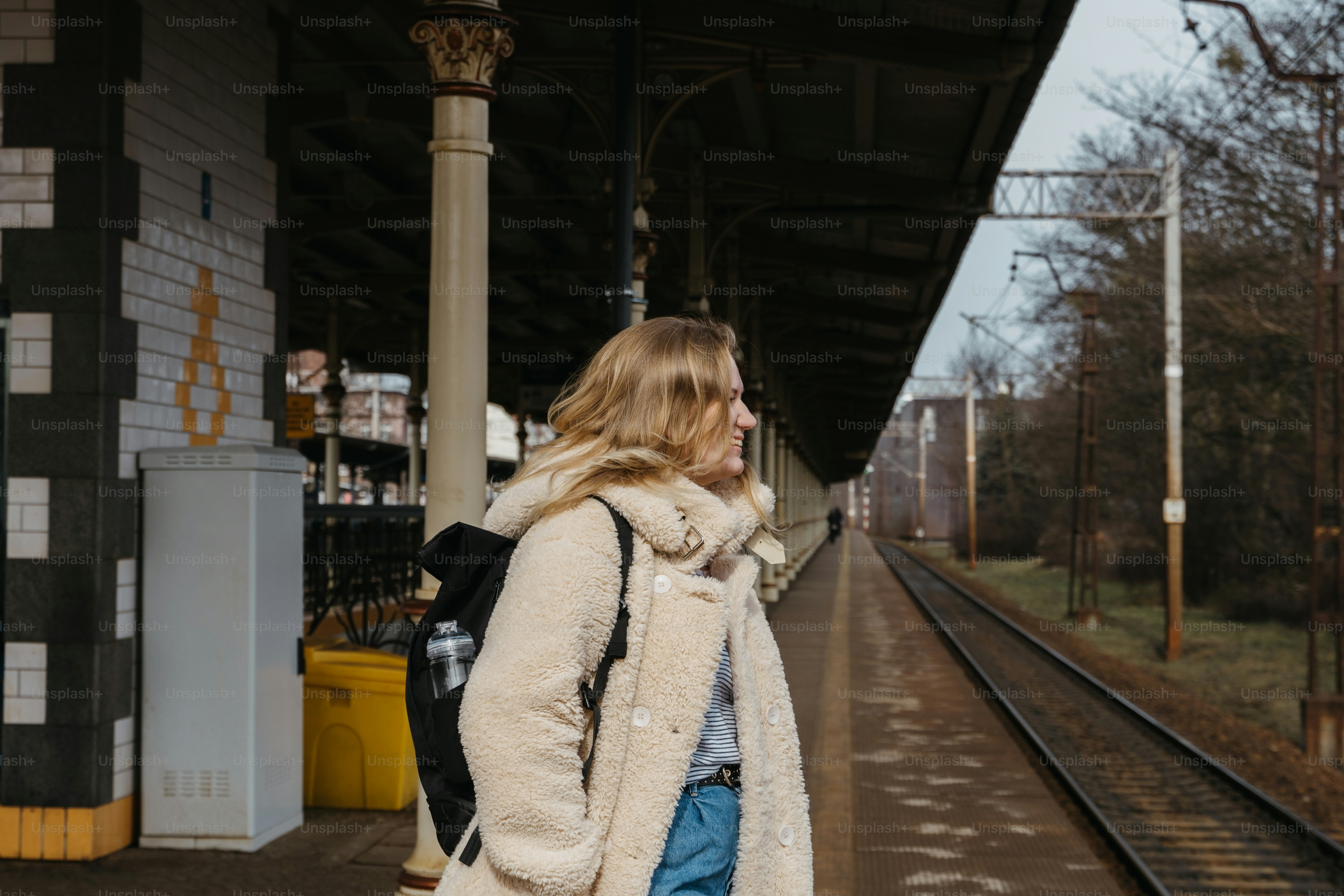 A woman standing on a train platform next to a train photo – Train ...