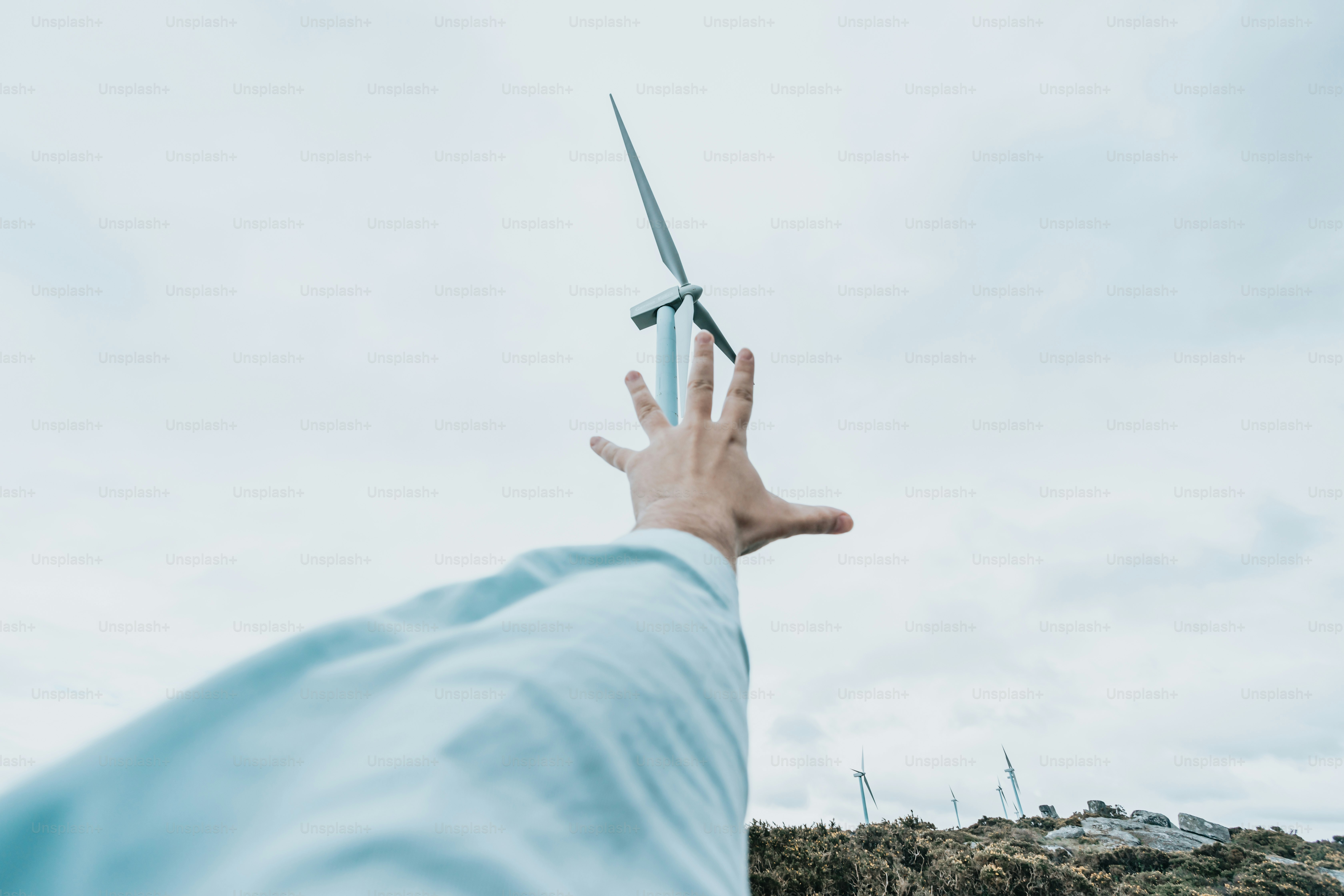 A hand reaching up towards a wind turbine photo – Environmental Image ...