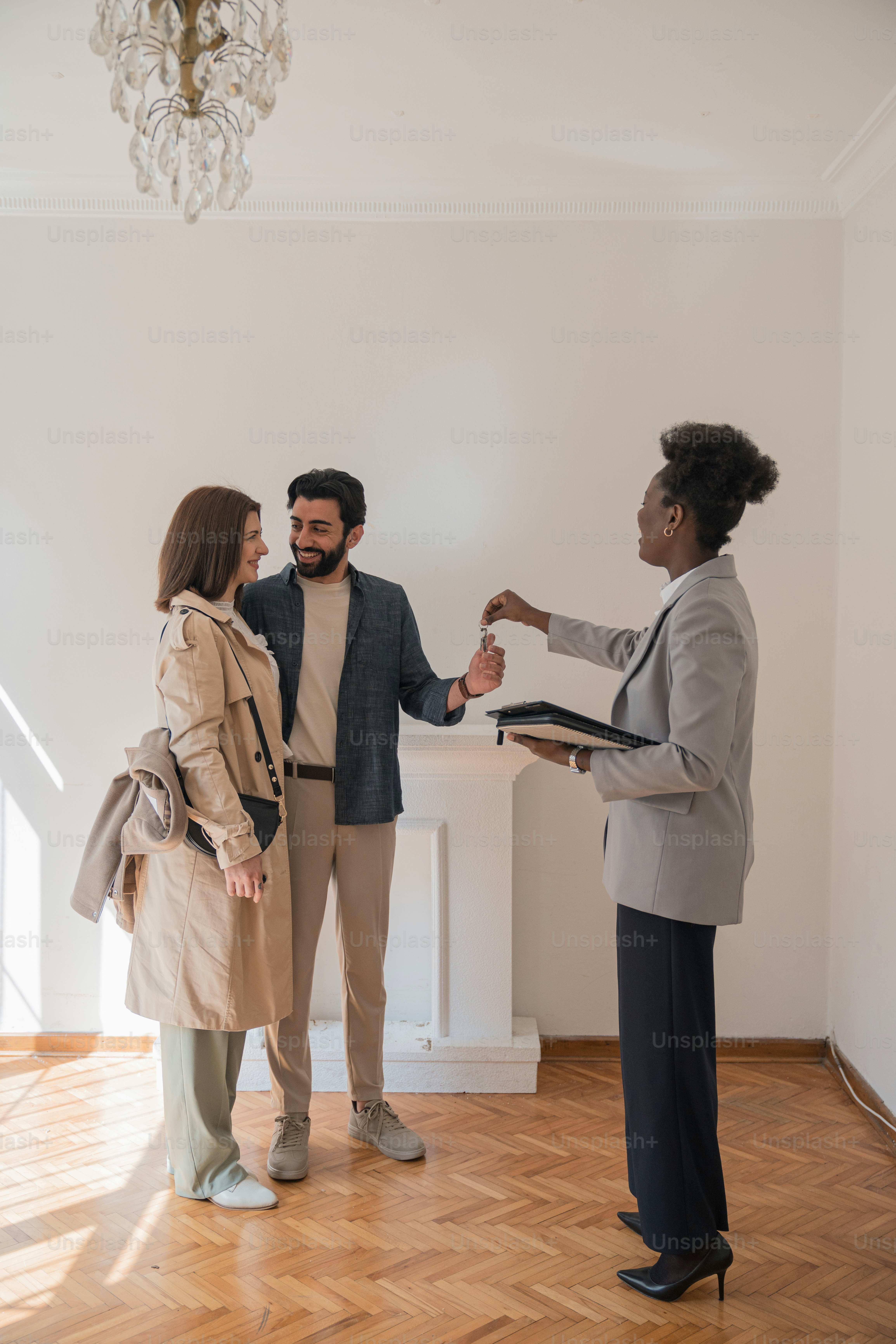 A man and a woman standing in a room shaking hands photo – Estate agent ...