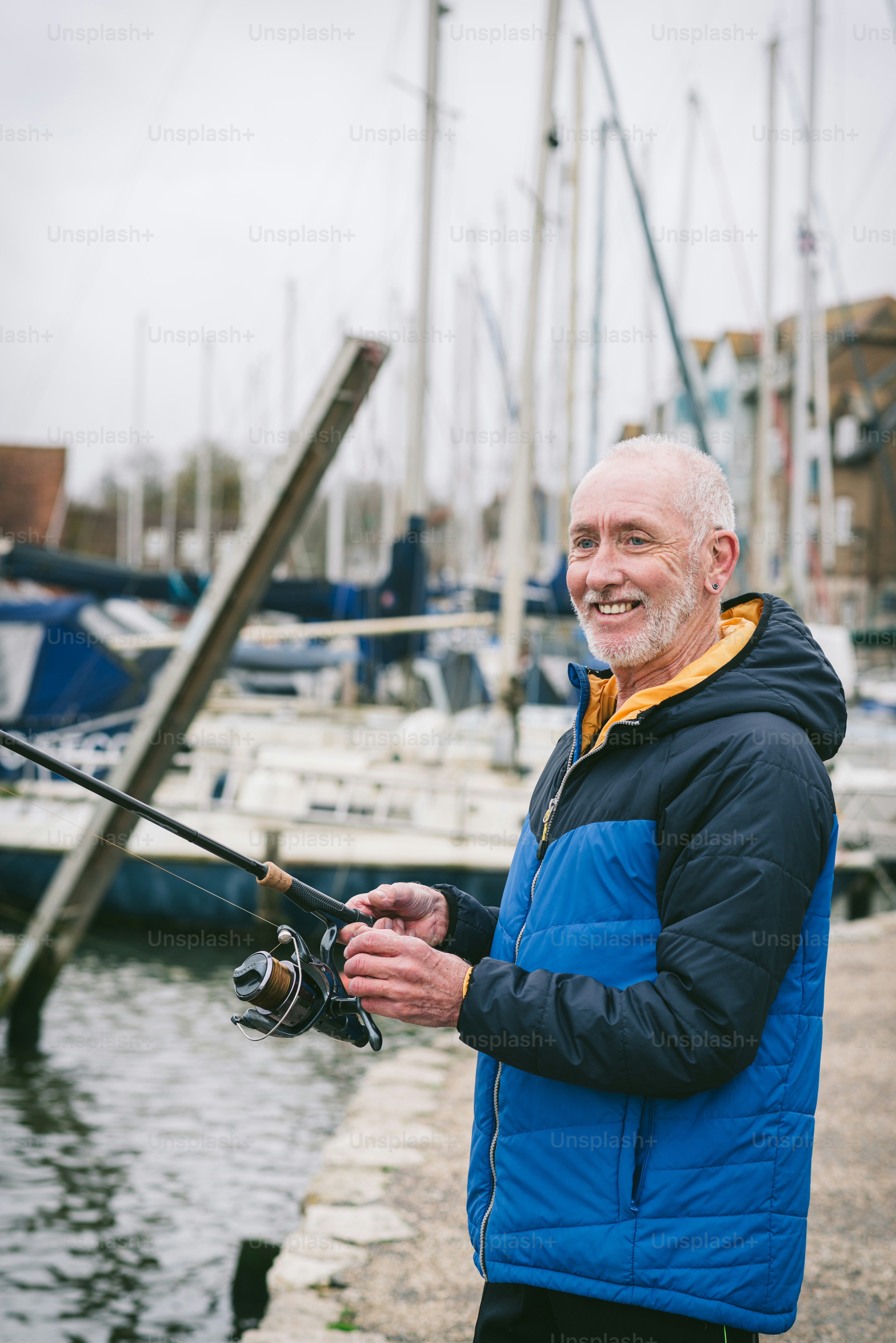 Foto Un hombre parado junto a un cuerpo de agua sosteniendo una caña de ...