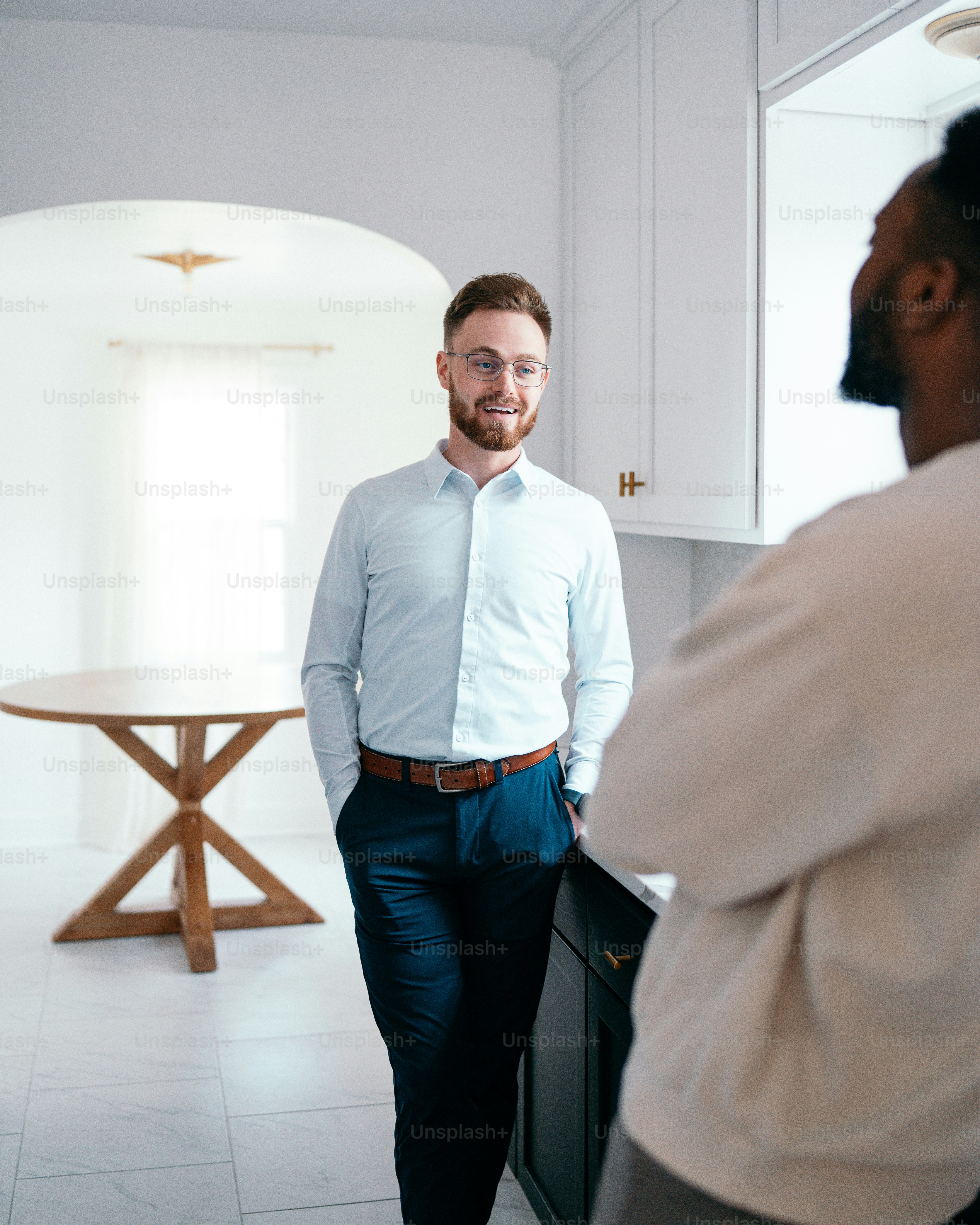 A man standing in a kitchen next to a table photo – Real estate Image ...