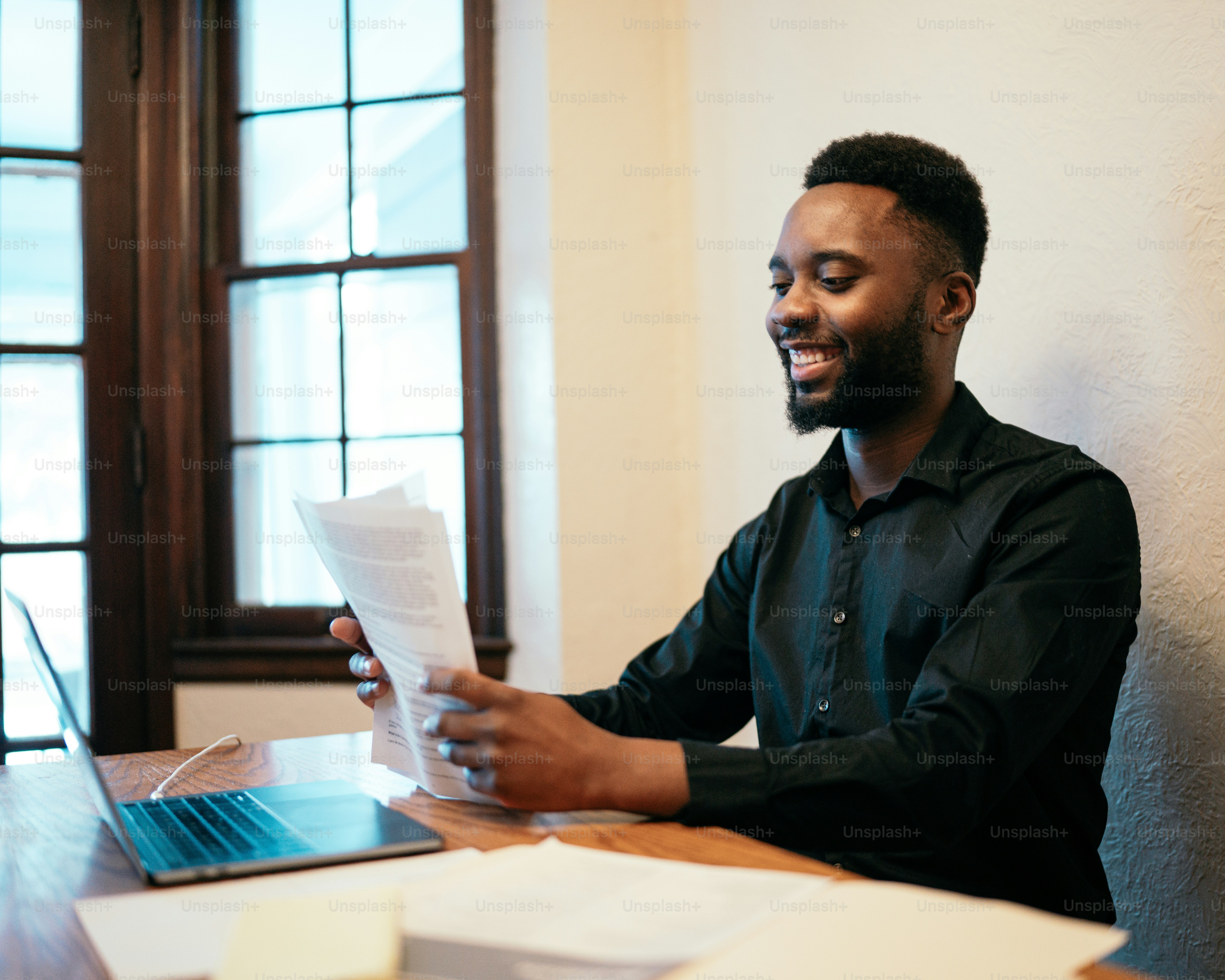 A man sitting at a table reading a piece of paper photo – Letters Image ...