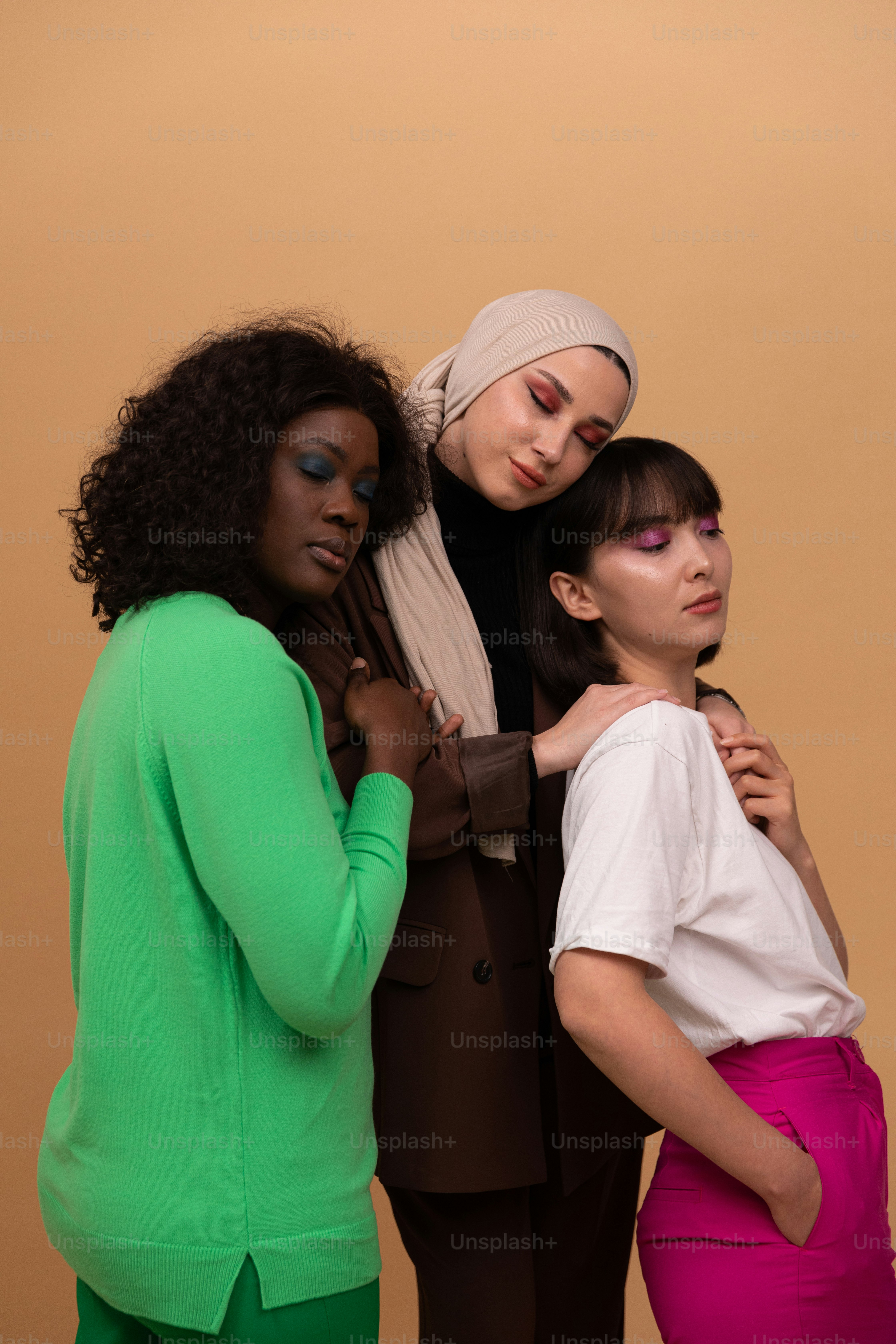 Three women standing next to each other in front of a wall photo ...