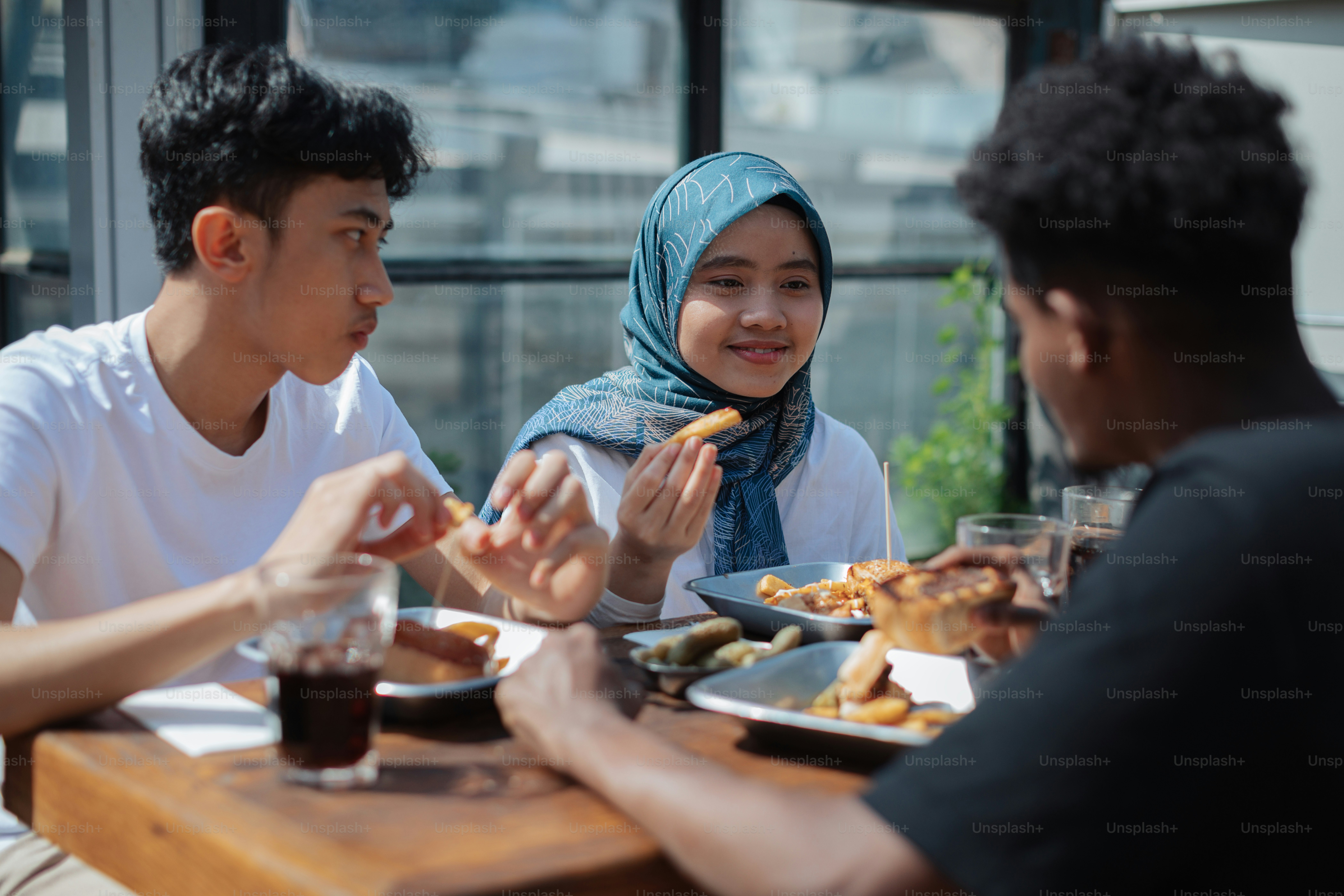 A group of people sitting around a table eating food photo – Lunch ...