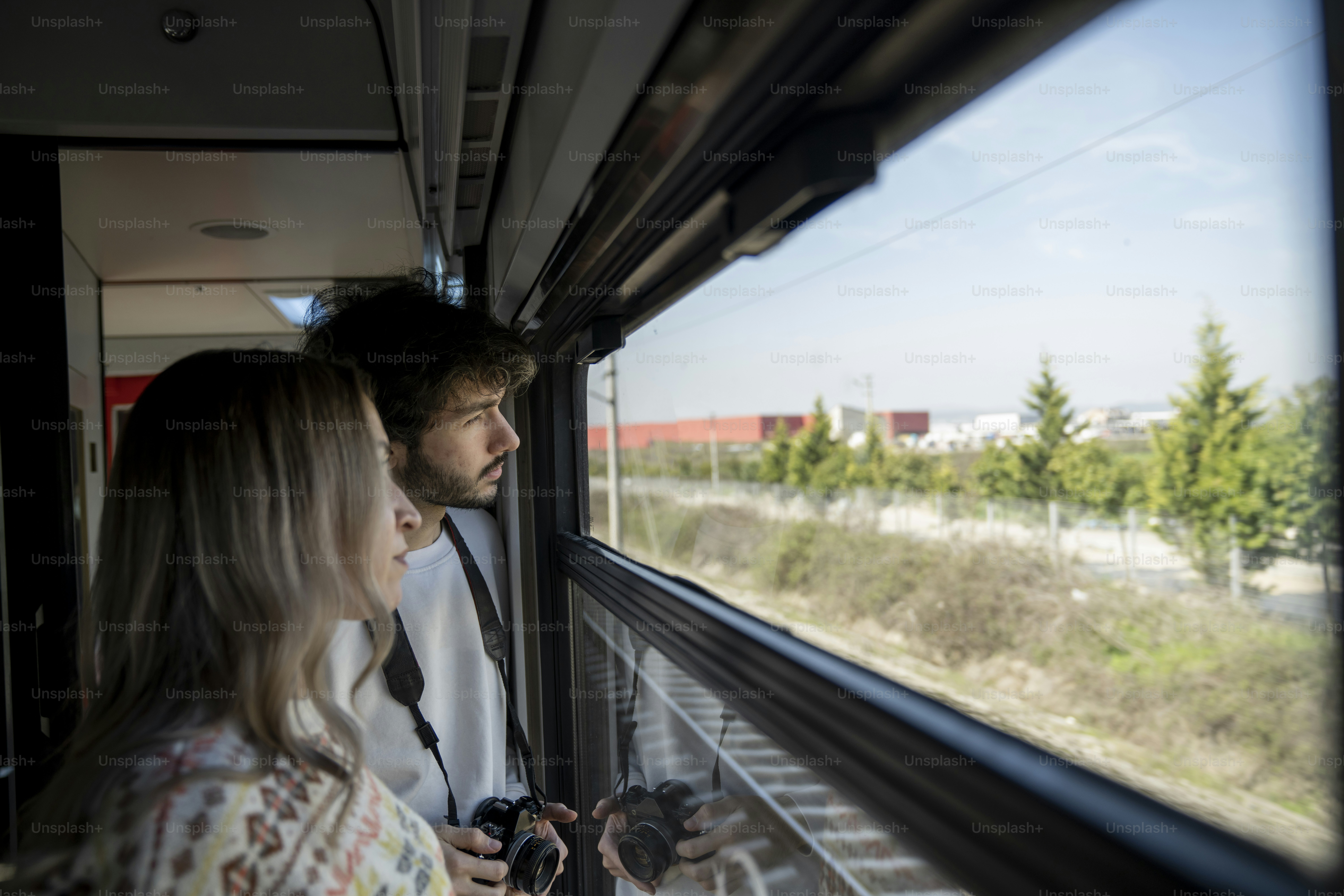 A man and a woman sitting on a train looking out the window photo ...