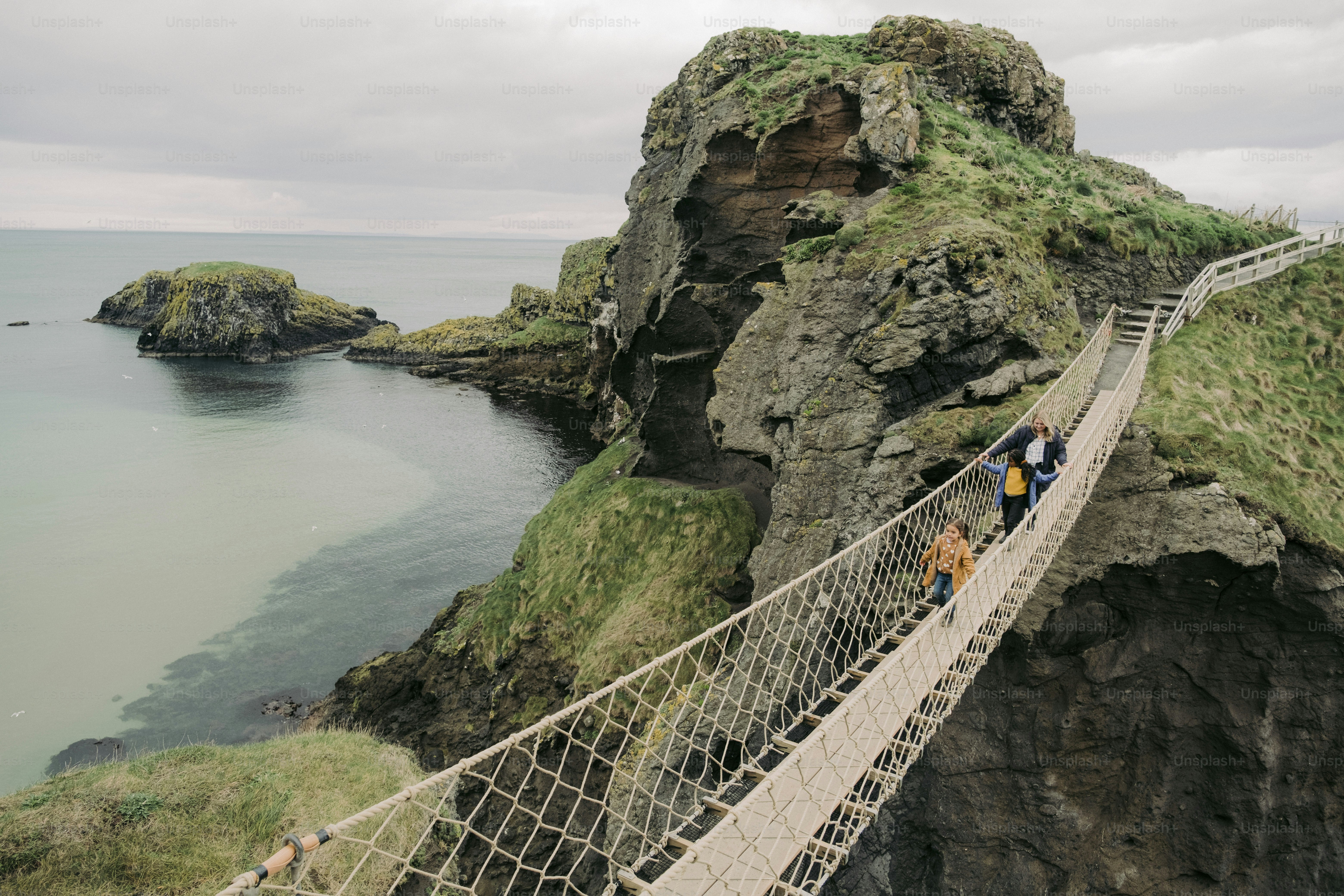 A group of people crossing a rope bridge over a body of water photo ...