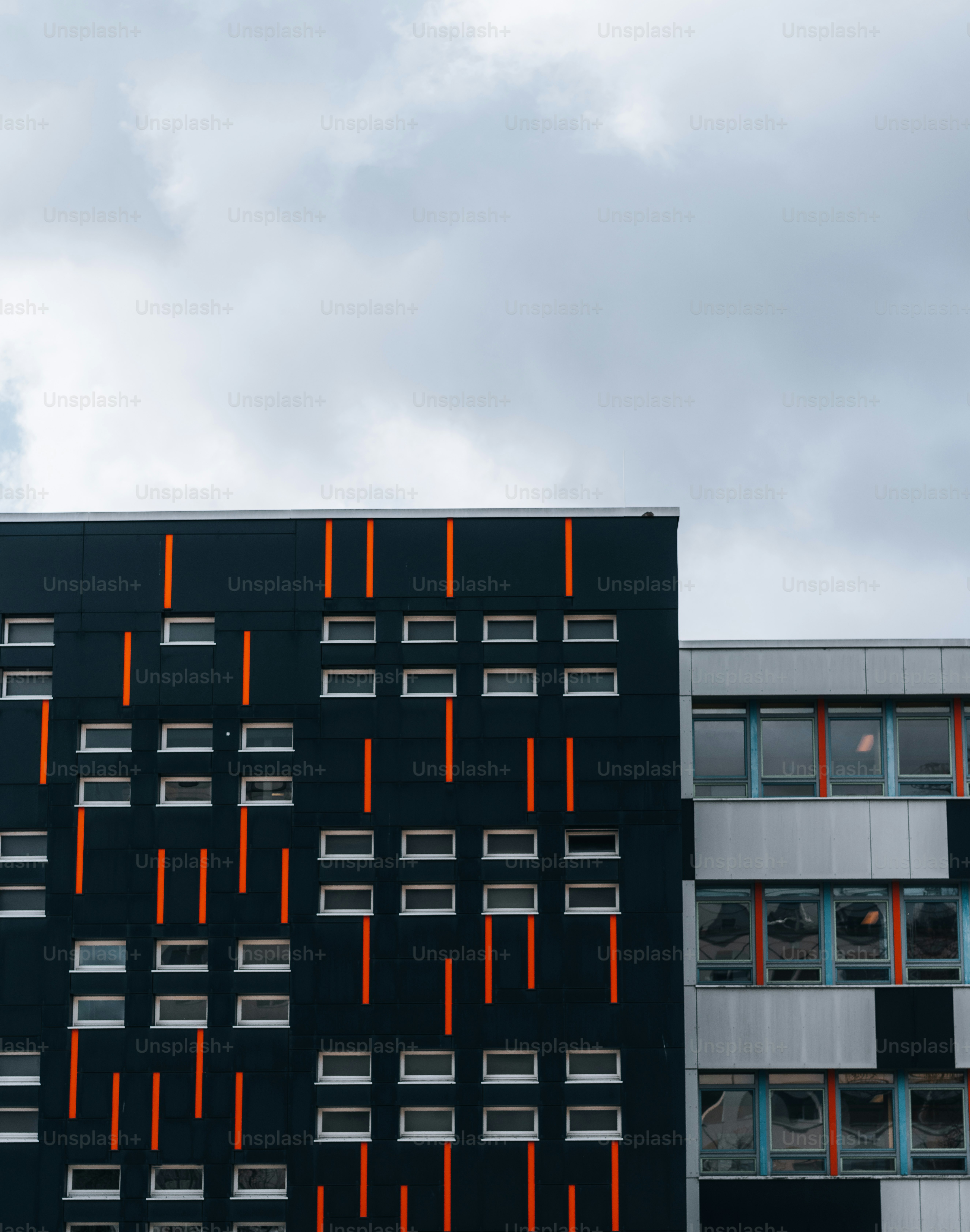 A black building with orange strips on the side of it photo – Wallpaper ...