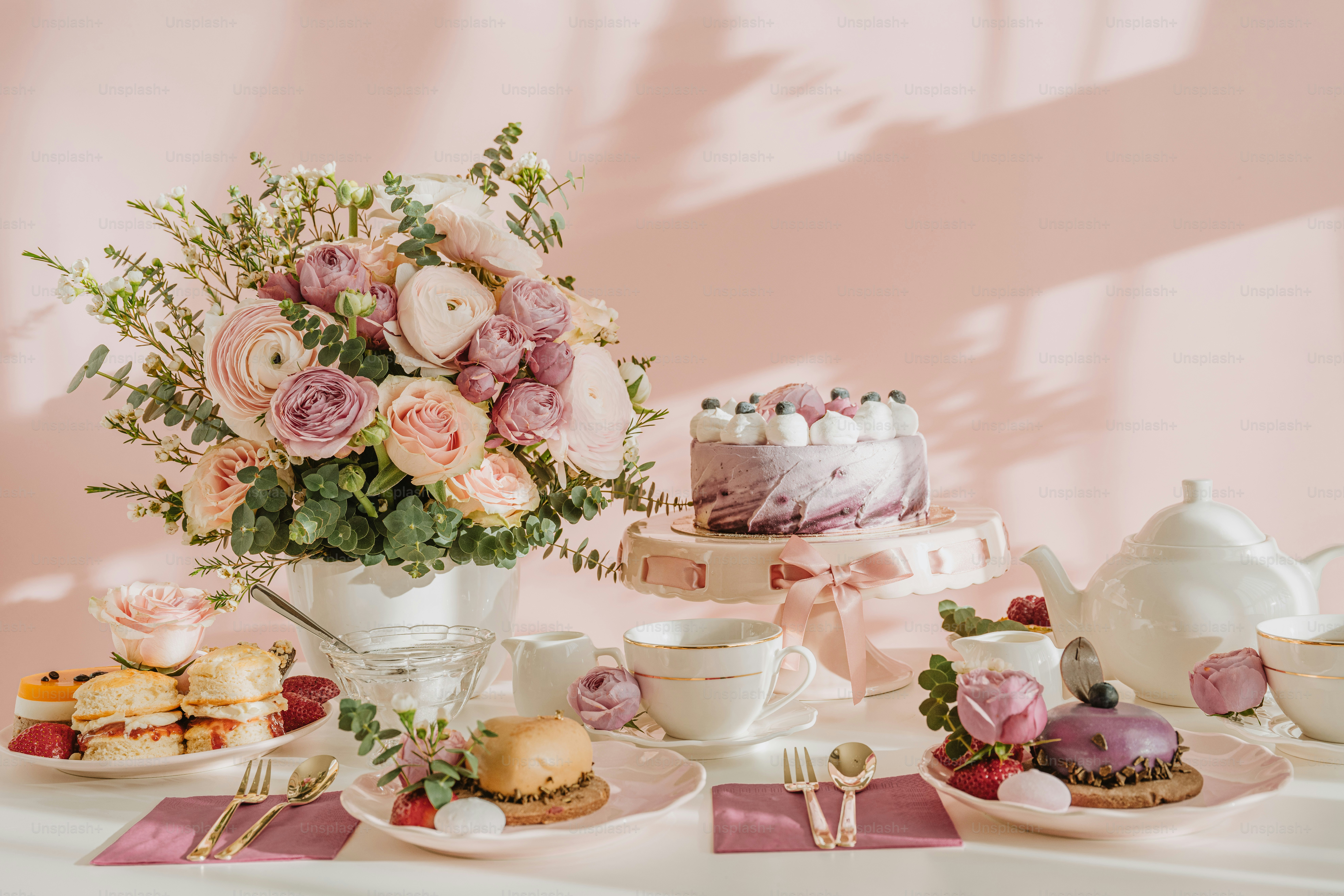 A white table topped with a tiered tray filled with cakes and desserts ...