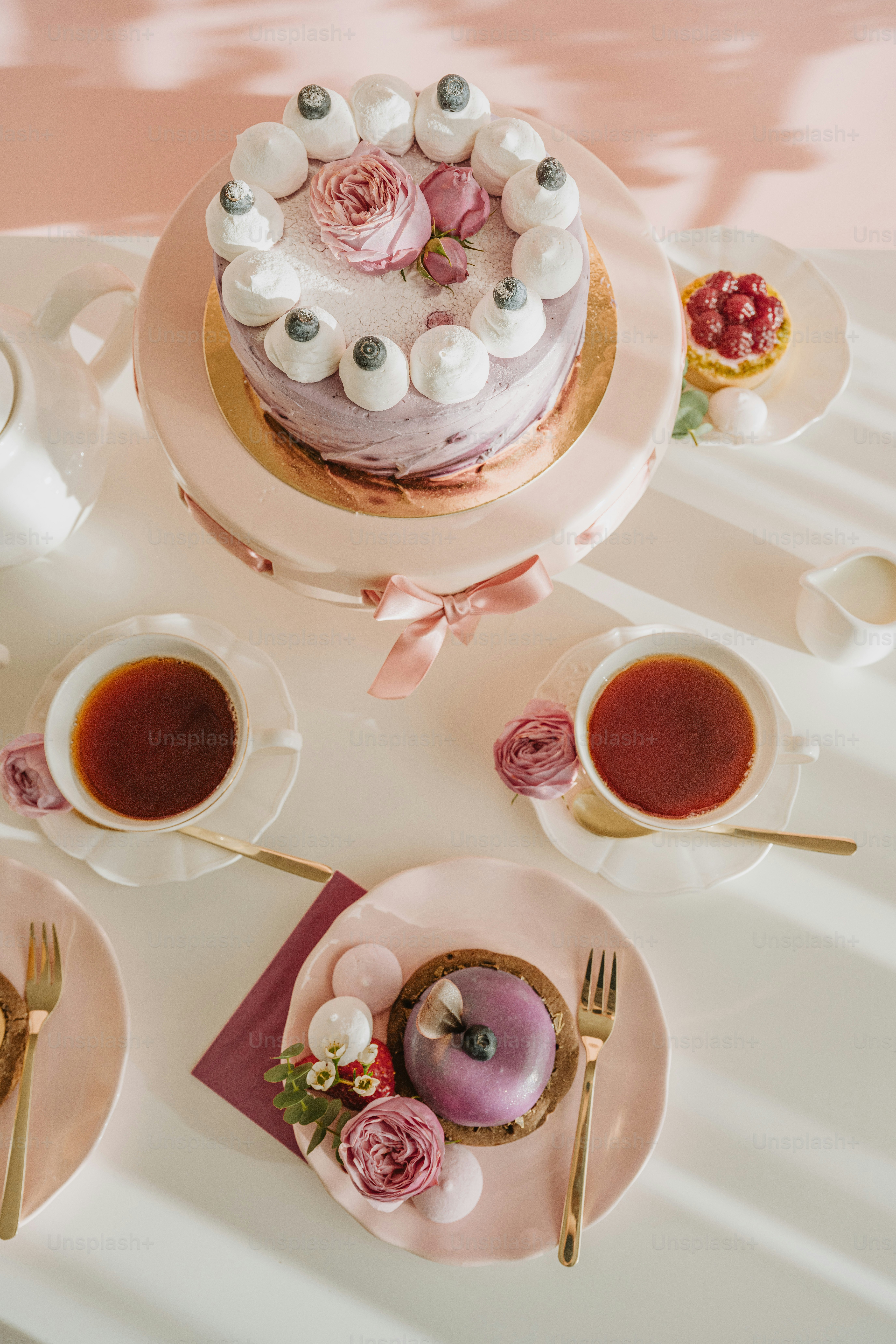 A white table topped with a tiered tray filled with cakes and desserts ...