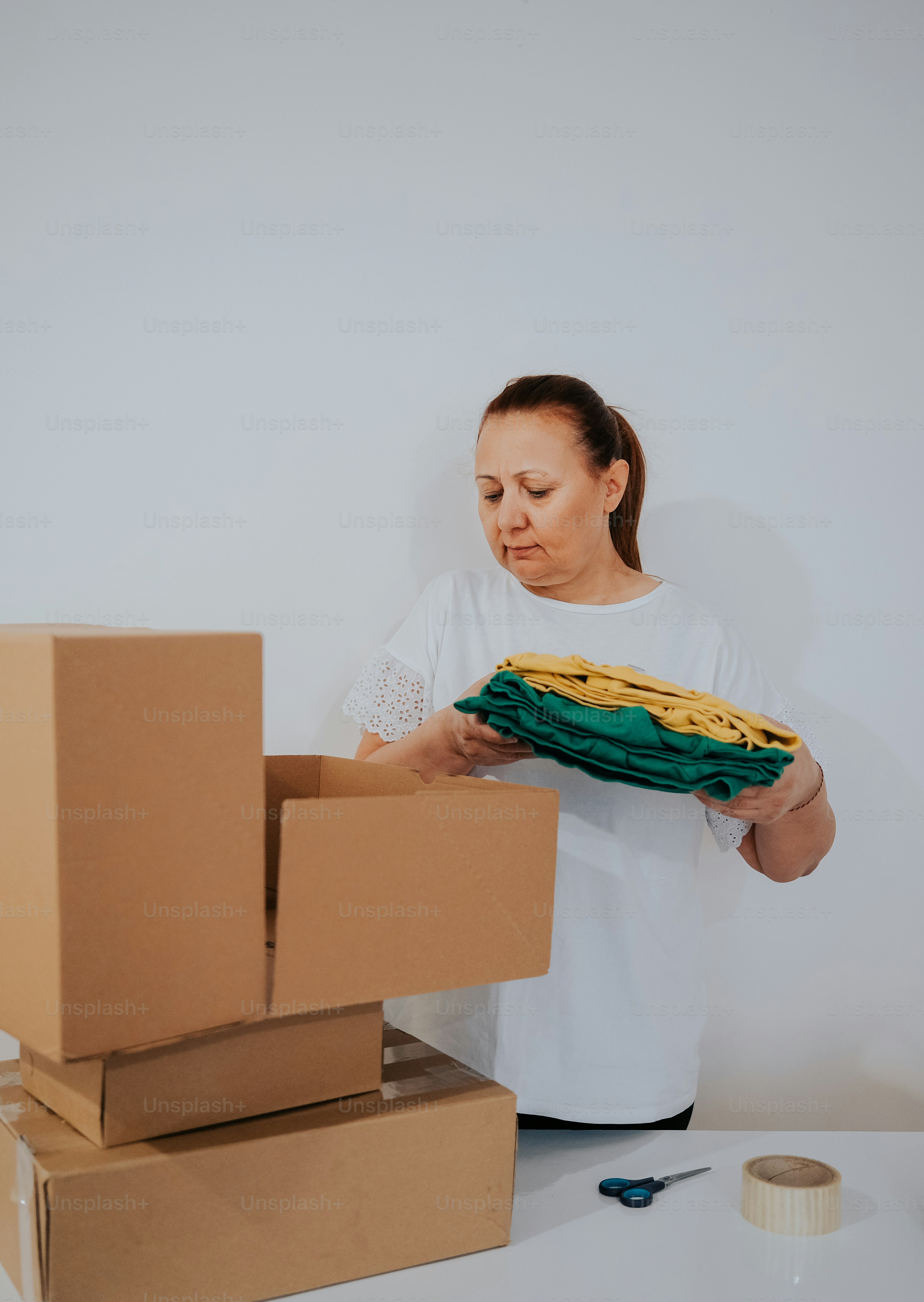 A woman holding a green cloth over a cardboard box photo – Carton box ...