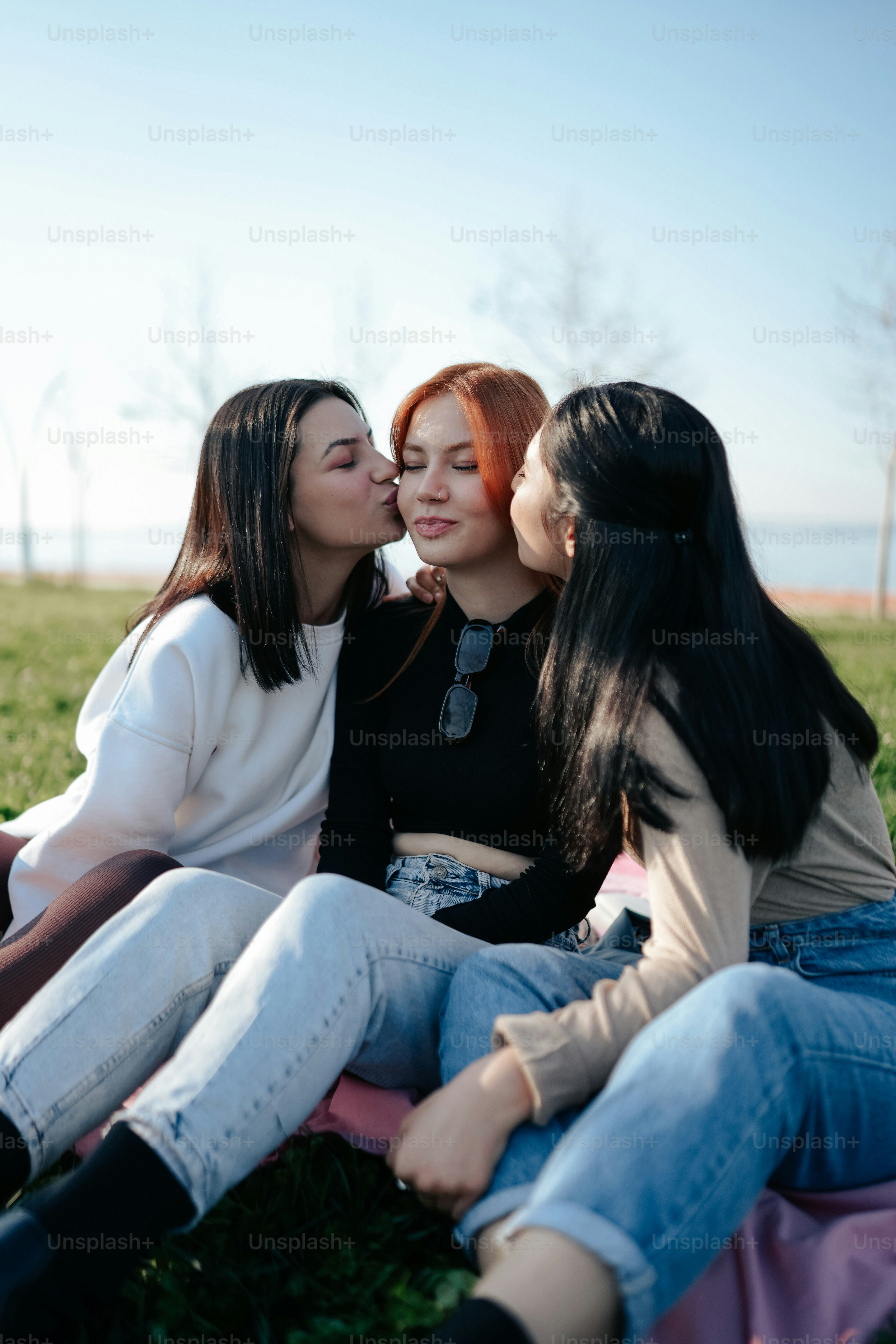 A group of women sitting on top of a lush green field photo – Women ...