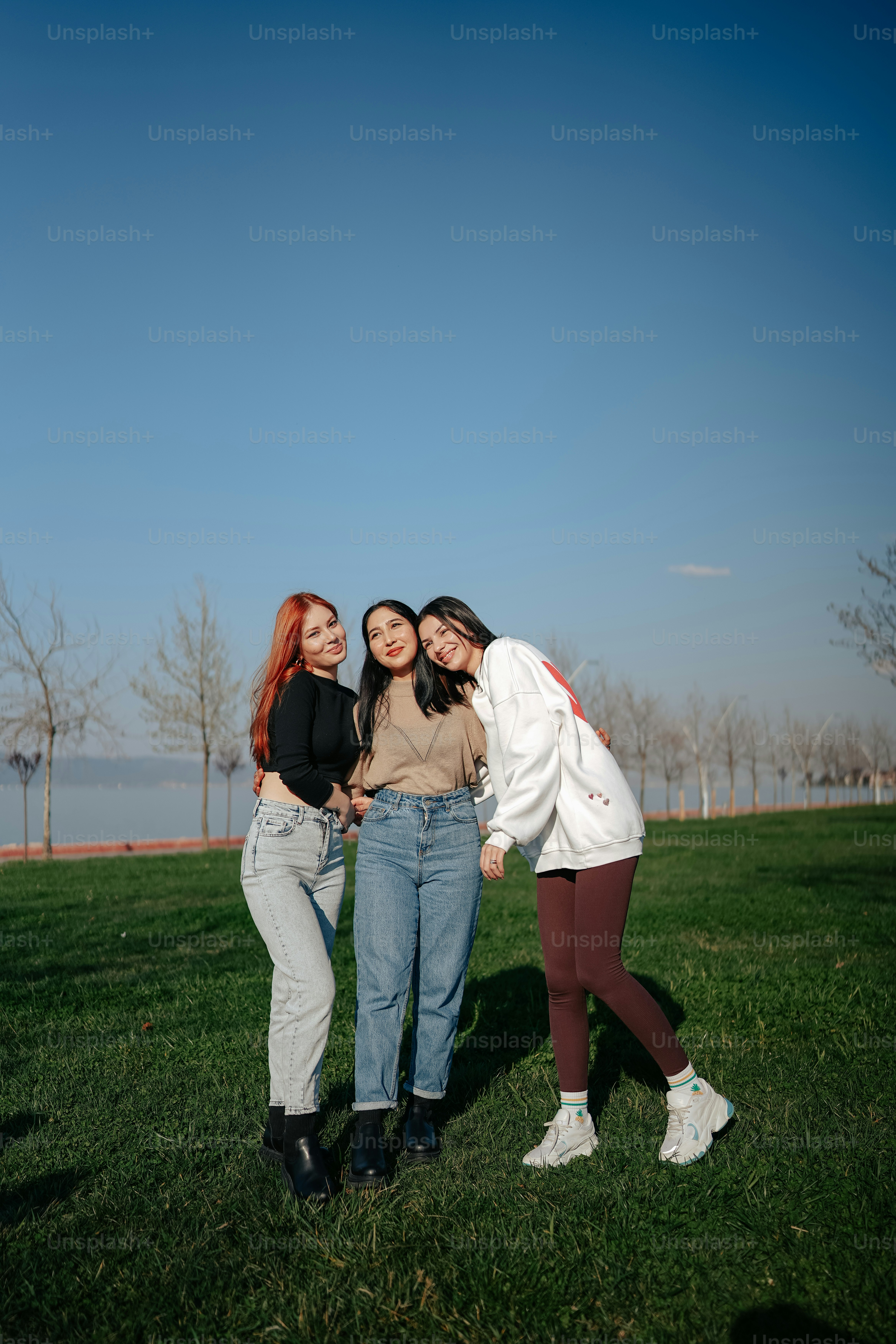 A group of three women standing next to each other photo – Outdoors ...