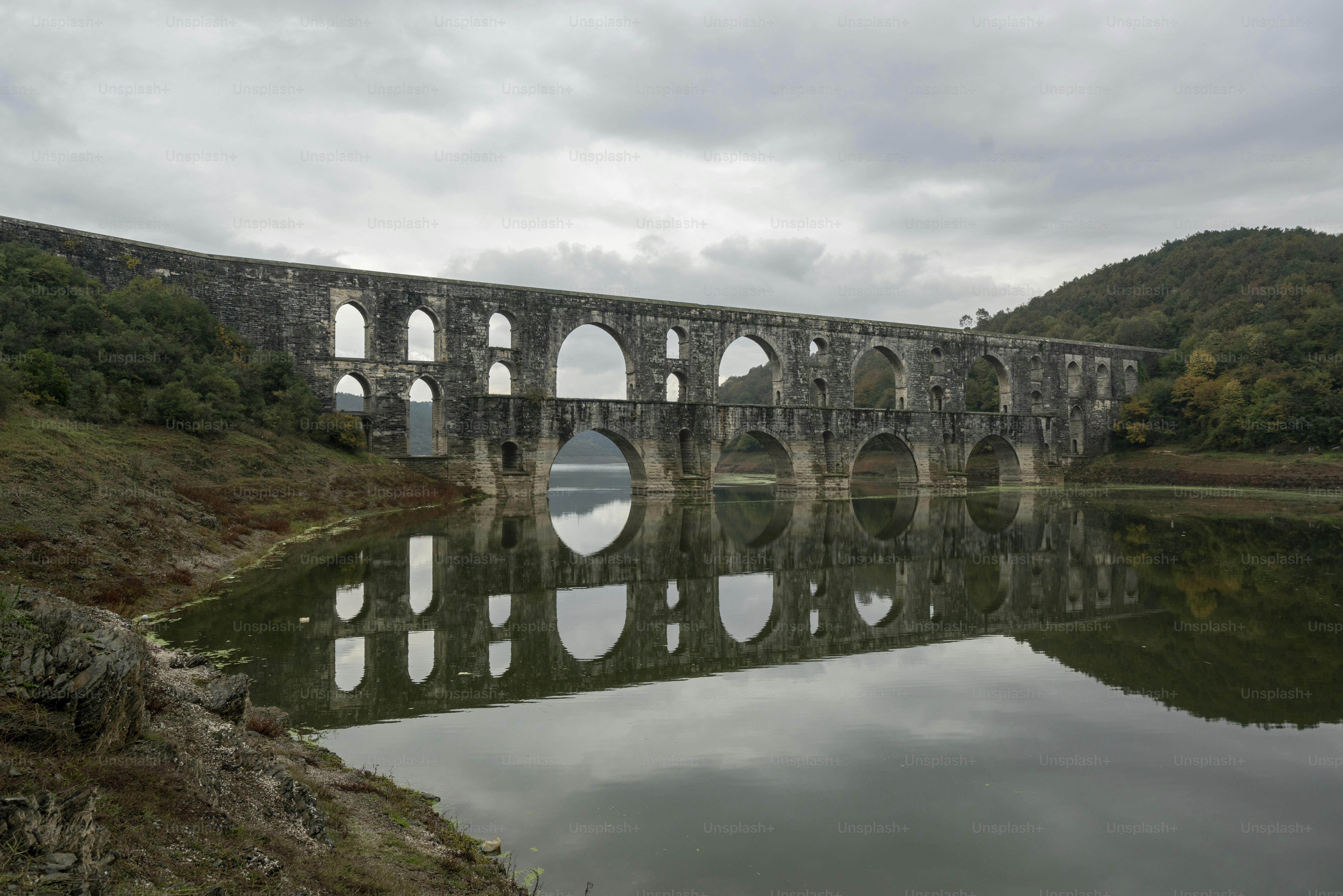 A large stone bridge over a body of water photo – Arch bridge Image on ...