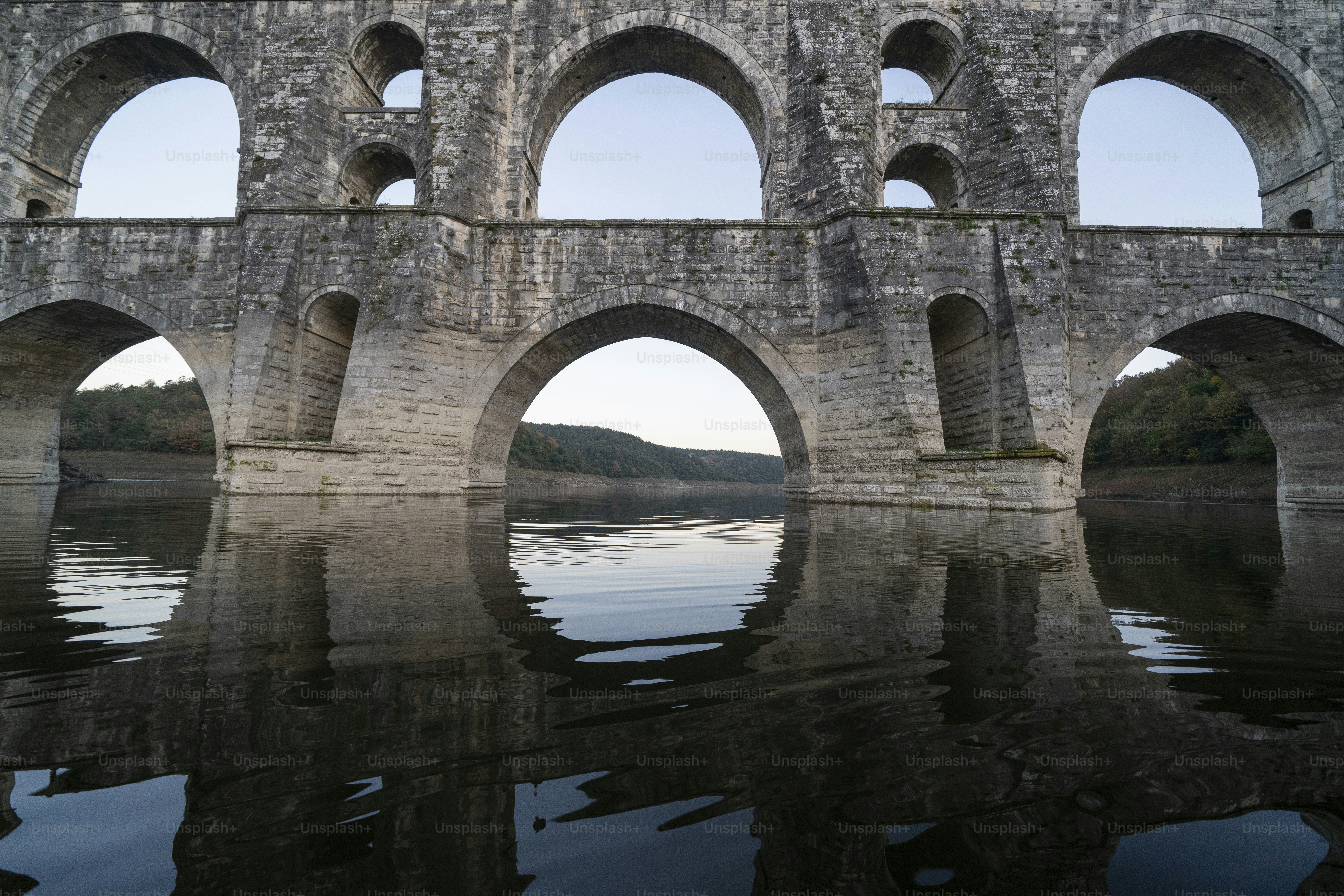 A large stone bridge over a body of water photo – Arch bridge Image on ...