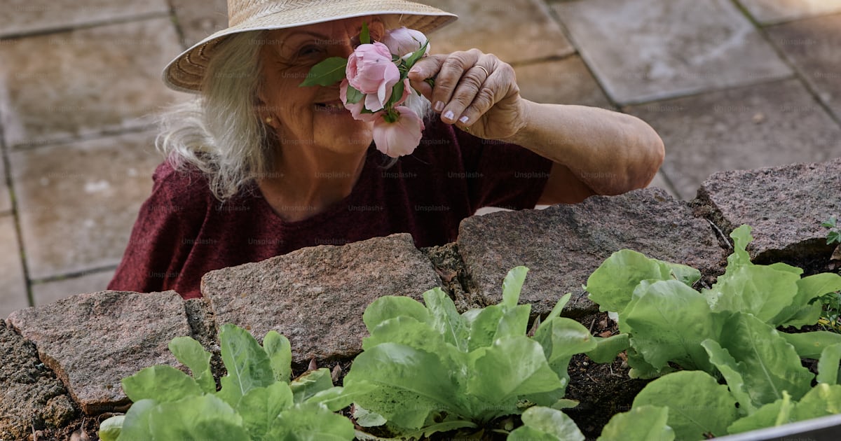 Una Mujer Con Un Sombrero De Paja Oliendo Una Flor Foto Imagen De Abuela En Unsplash