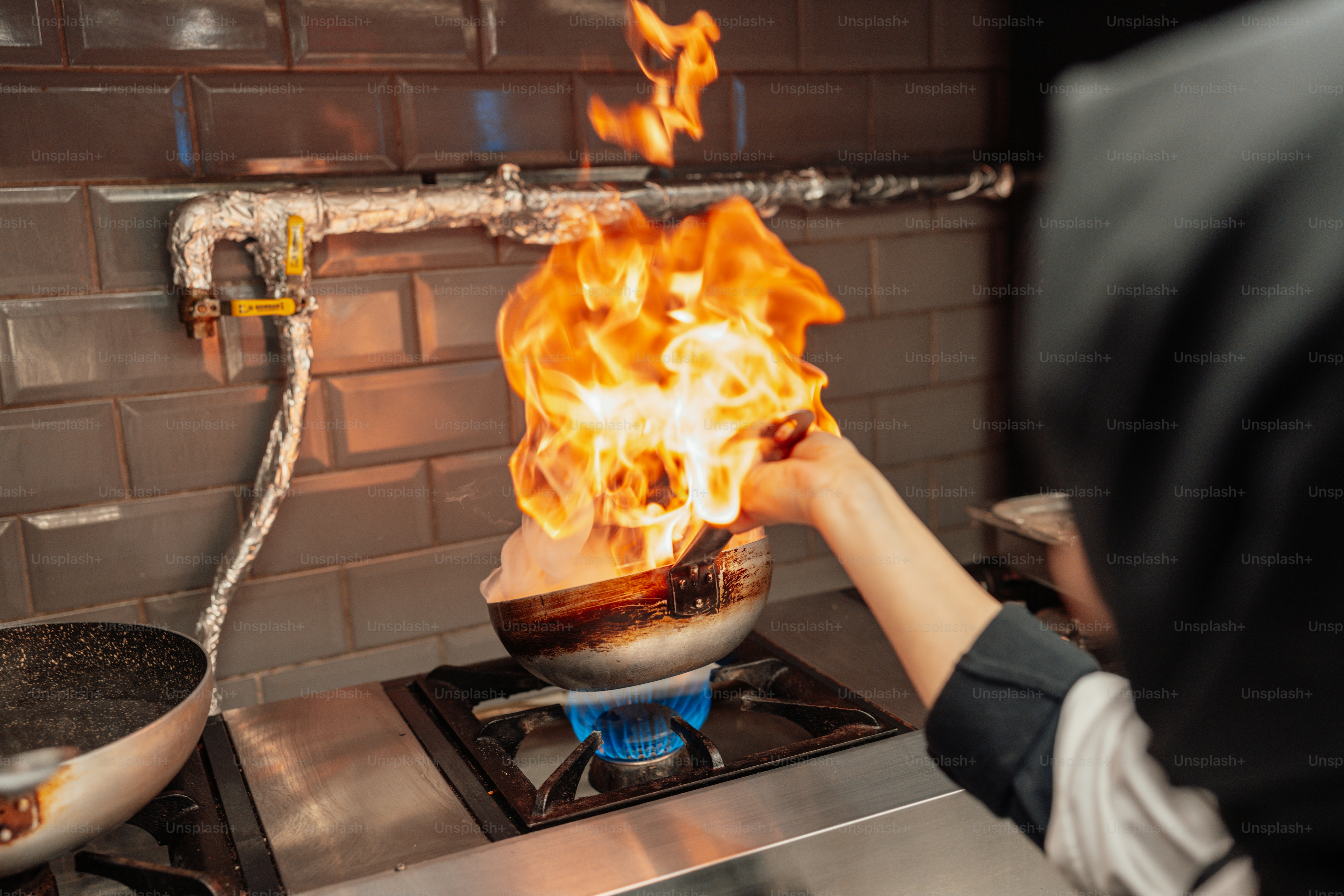 A person cooking on a stove with flames photo – Frying pan Image on ...