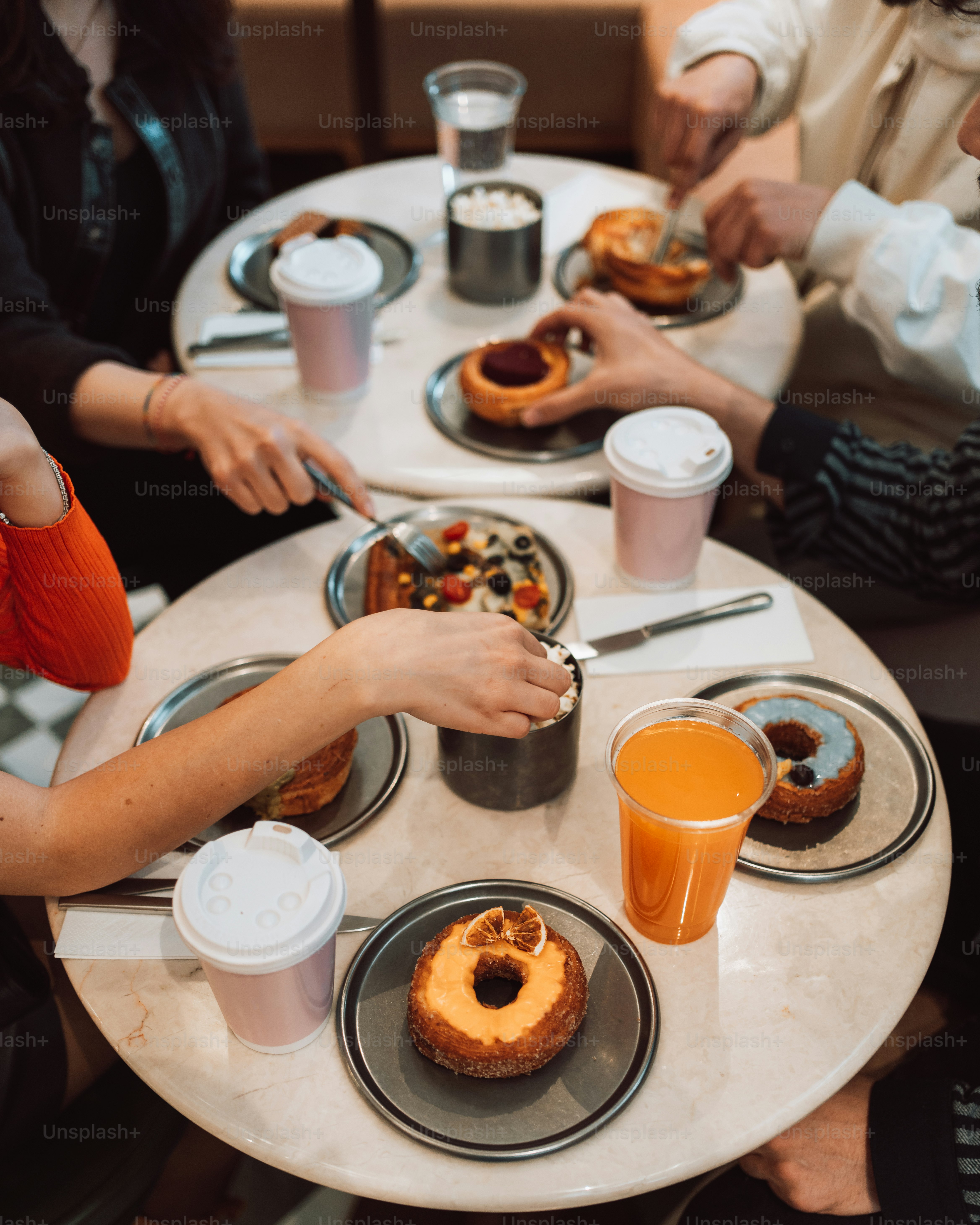 A group of people sitting at a table eating doughnuts photo – Eating ...