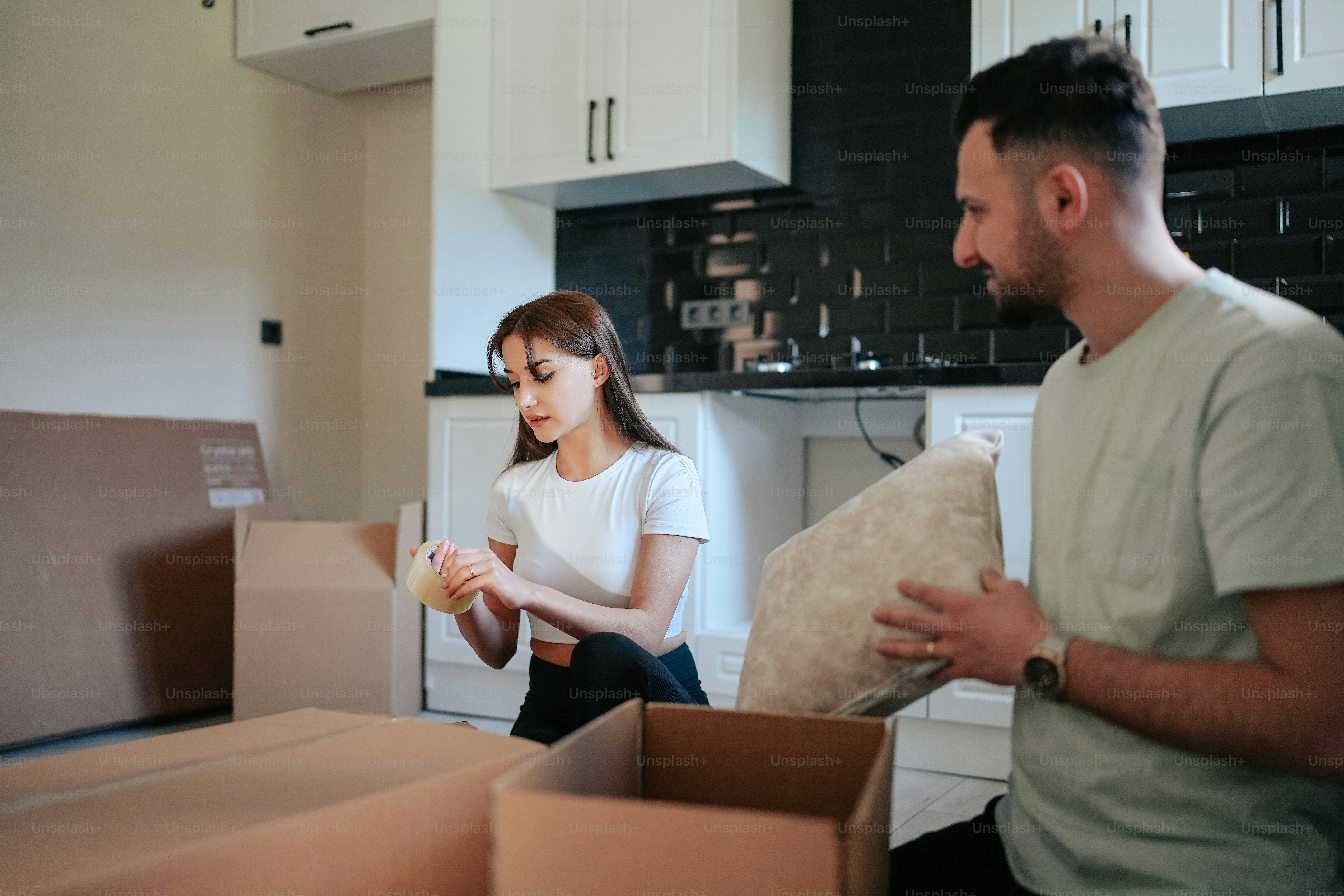A man and a woman unpack boxes in a kitchen photo – Purchaser Image on ...