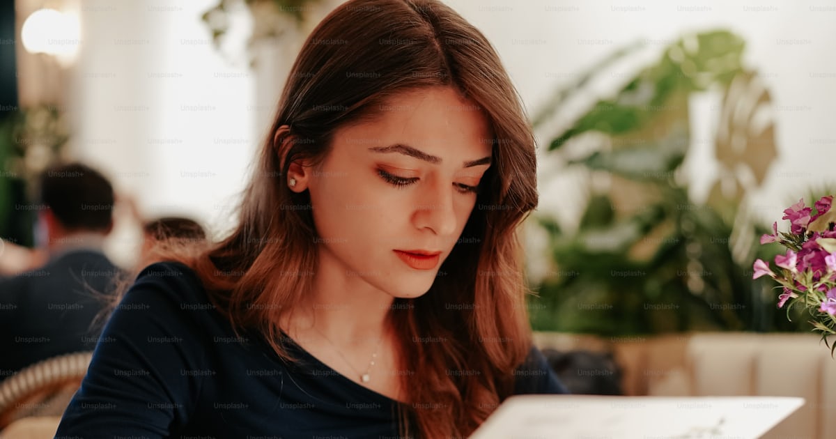 Una Mujer Sentada En Una Mesa Leyendo Un Periódico Foto Imagen De