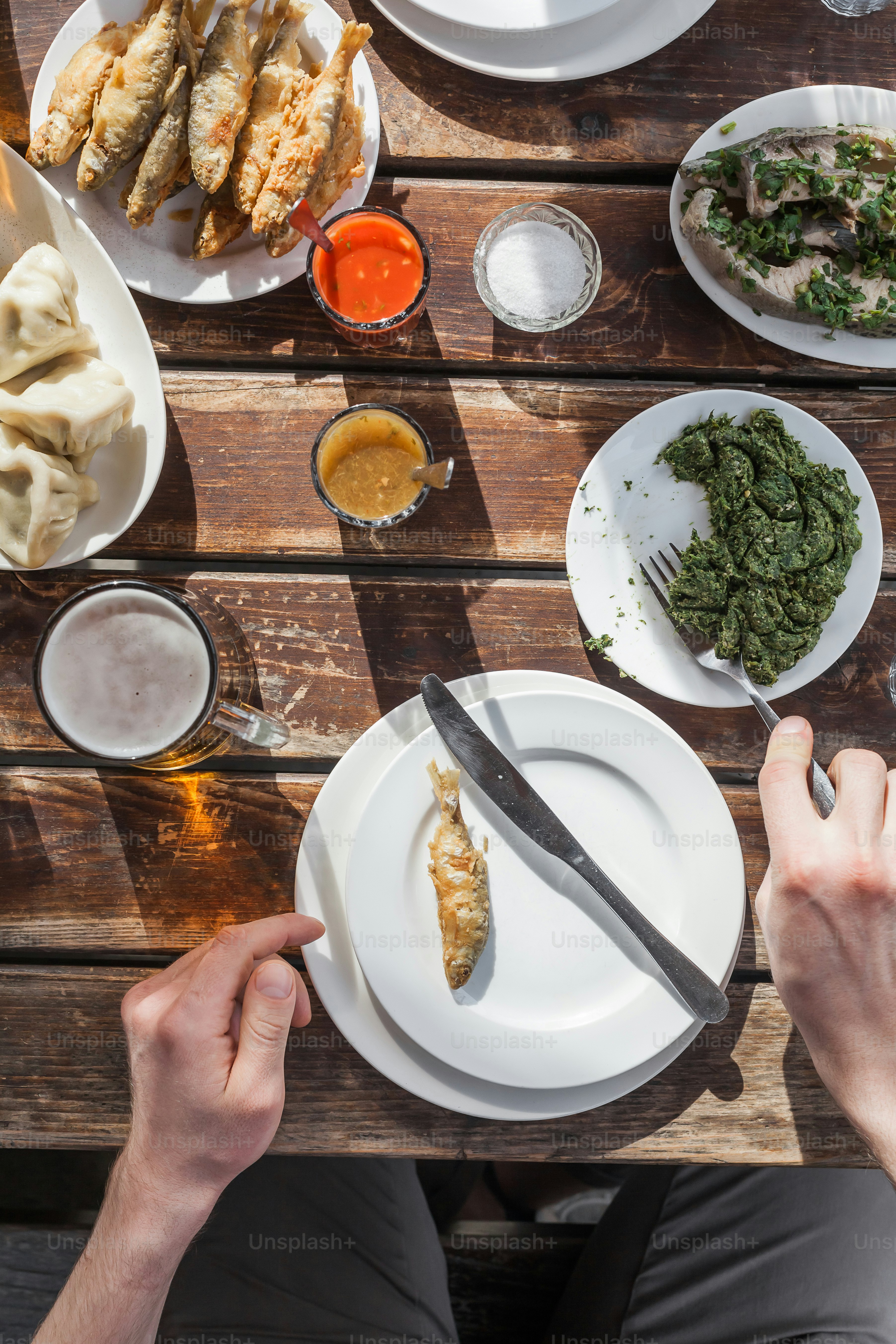 A couple of people sitting at a table with plates of food photo – Beer ...