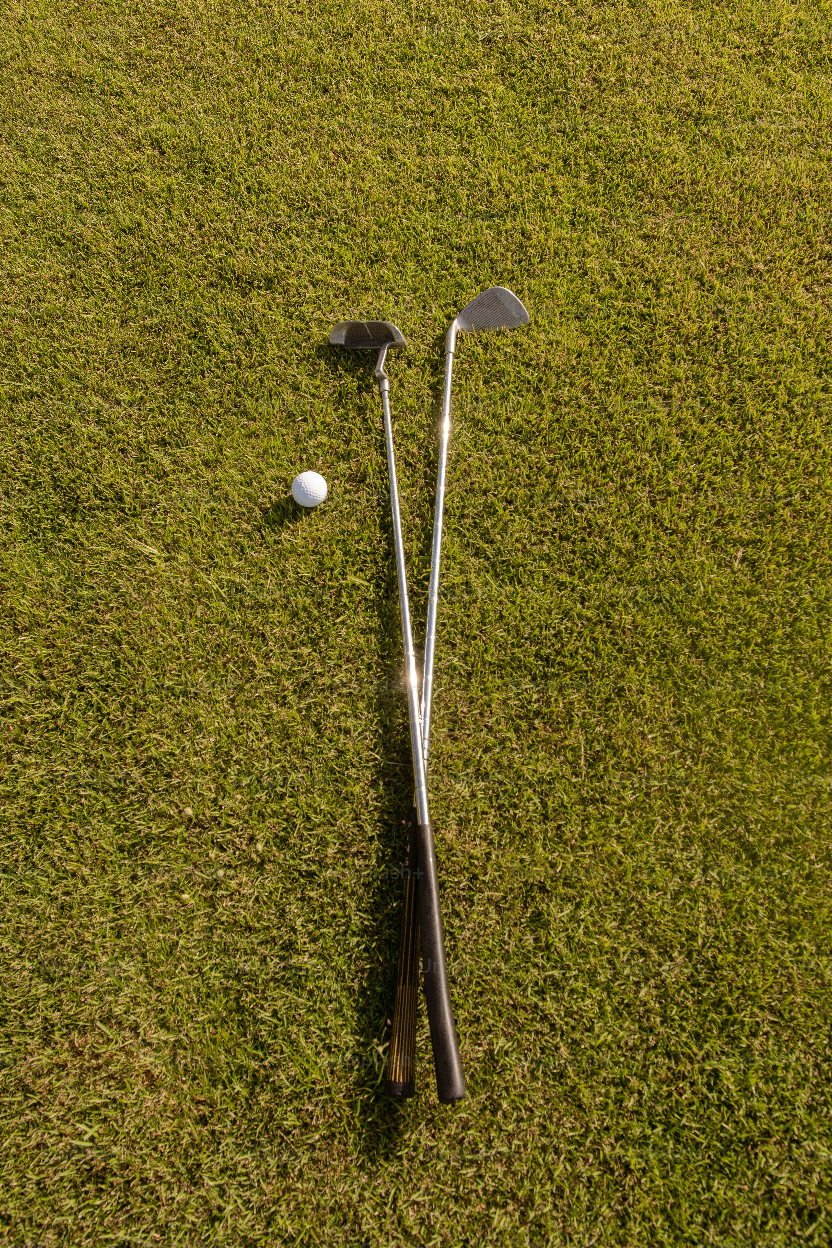 Two golf clubs and a ball laying on the grass photo – Golf clubs Image ...