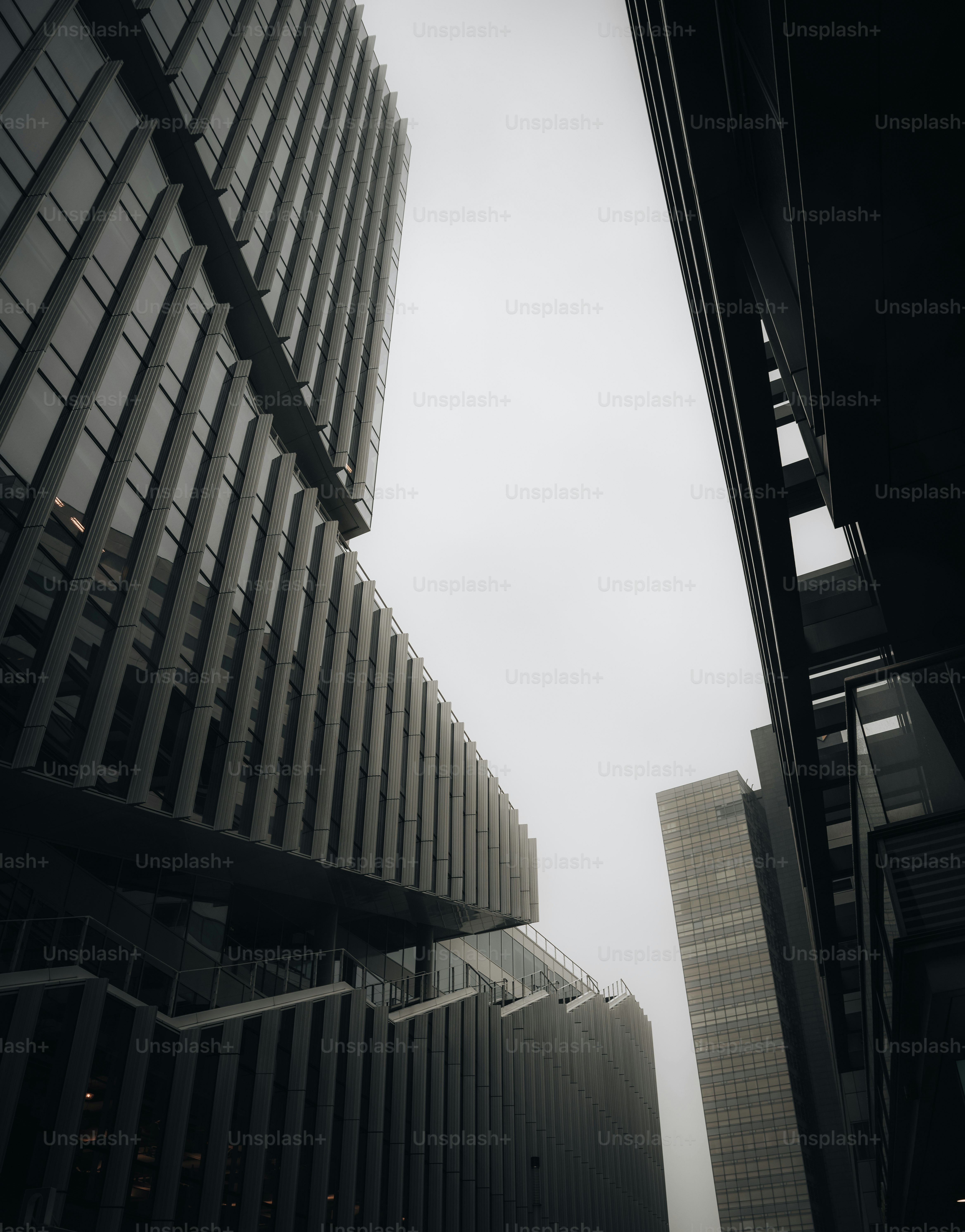 Foto Una foto en blanco y negro de dos edificios altos – Edificio moderno Imagen en Unsplash