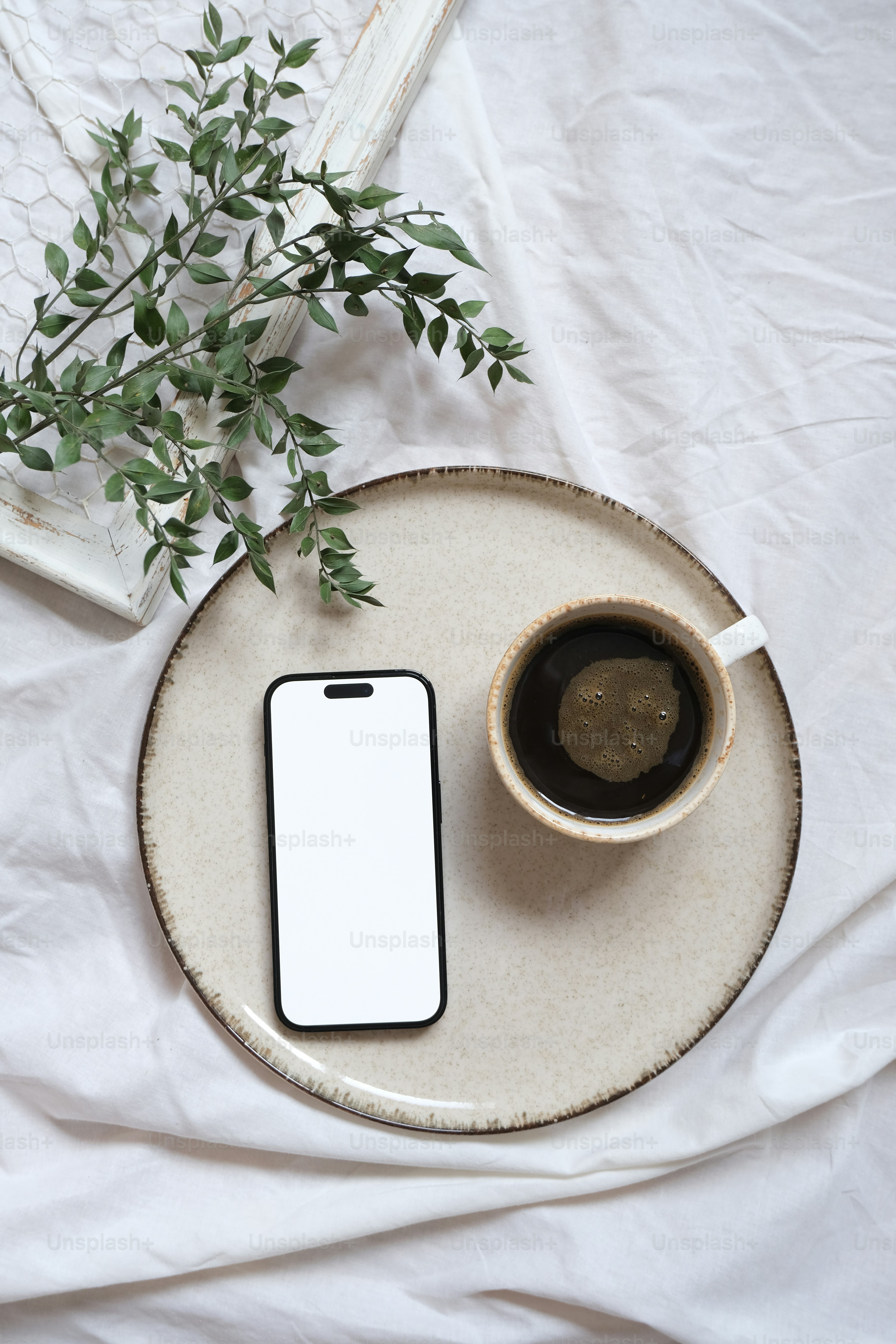 A cup of coffee and a cell phone on a plate photo – Phone on table ...