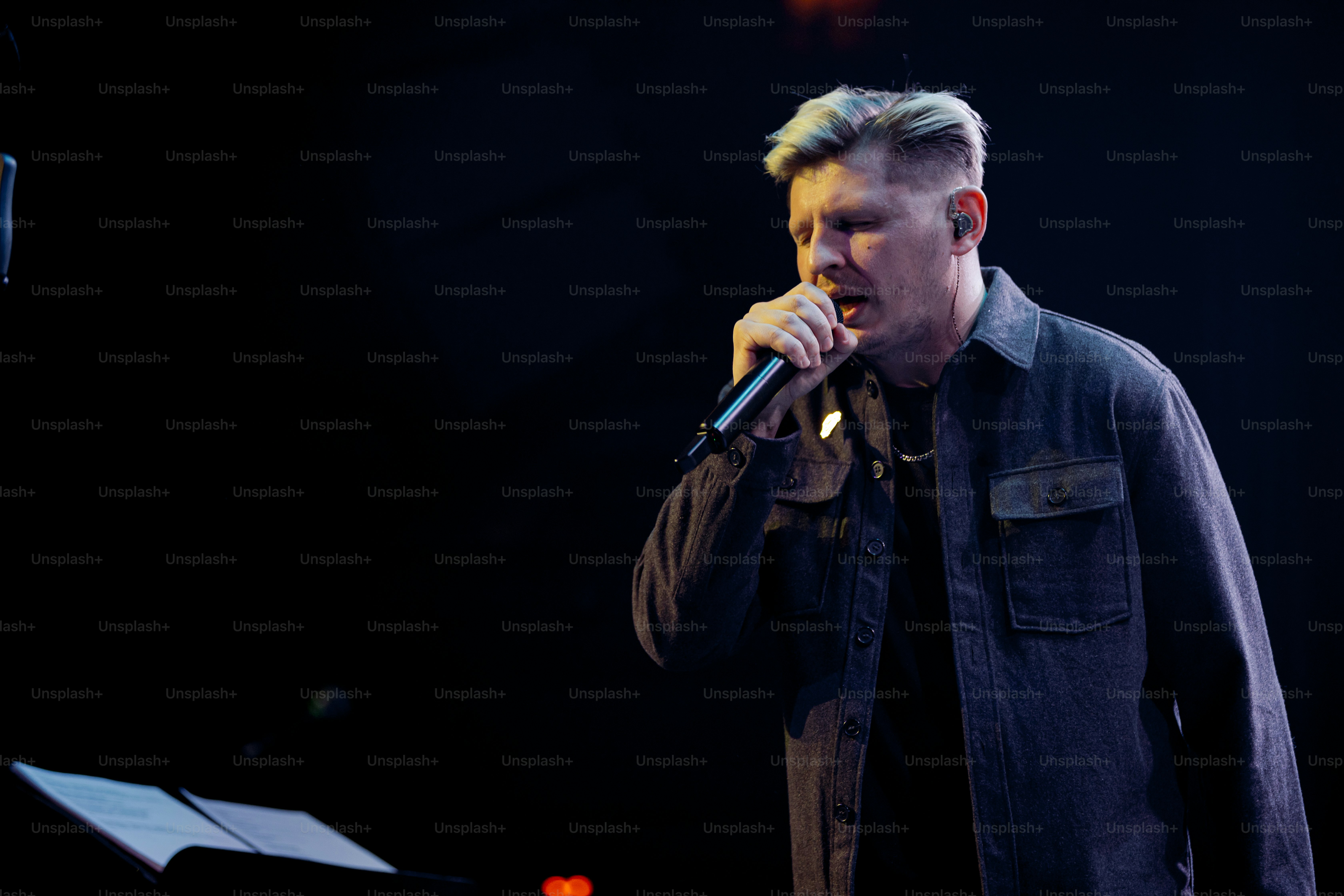 A man singing into a microphone on stage photo – Stage Image on Unsplash