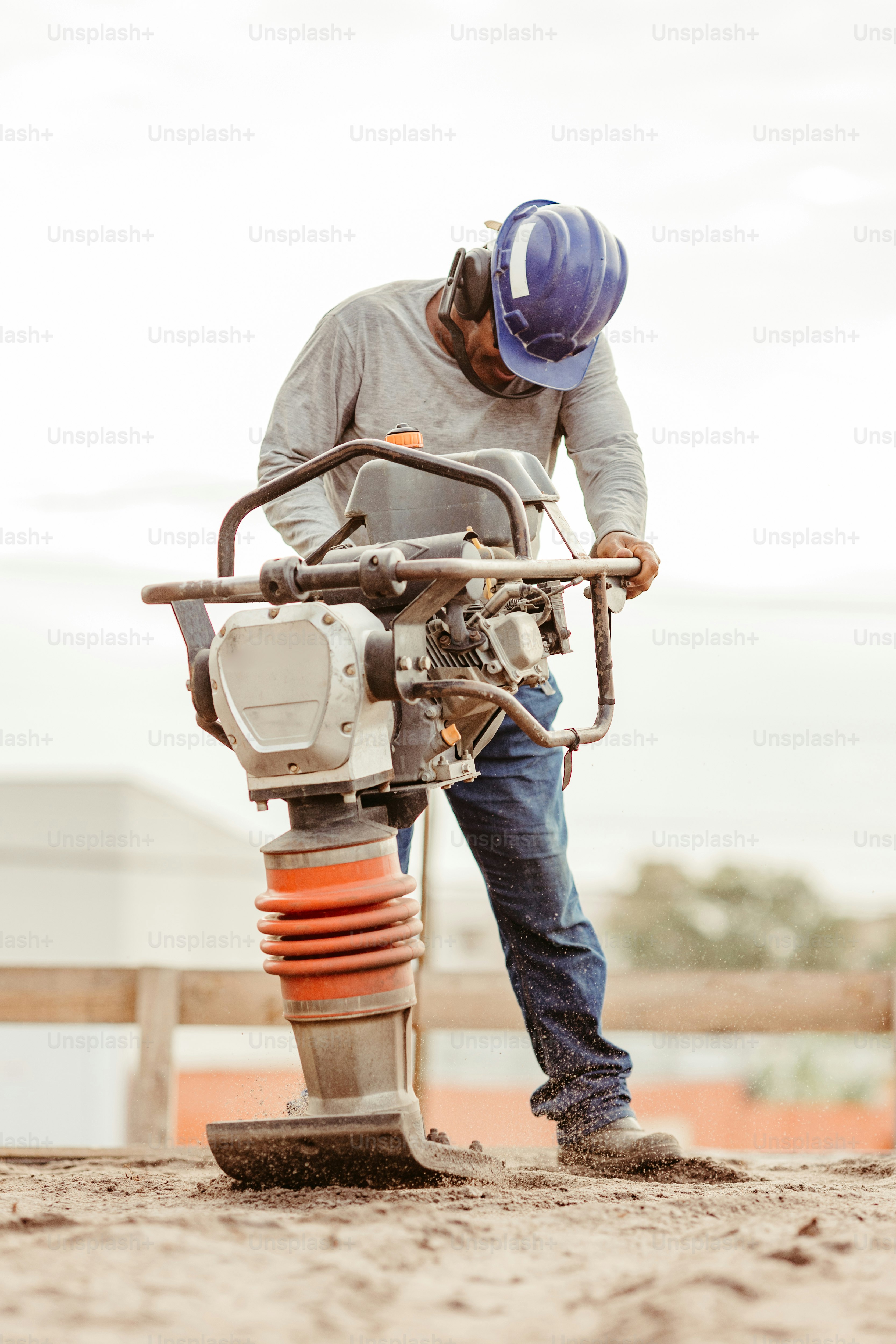A man in a hard hat working on a machine photo – Building foundation ...