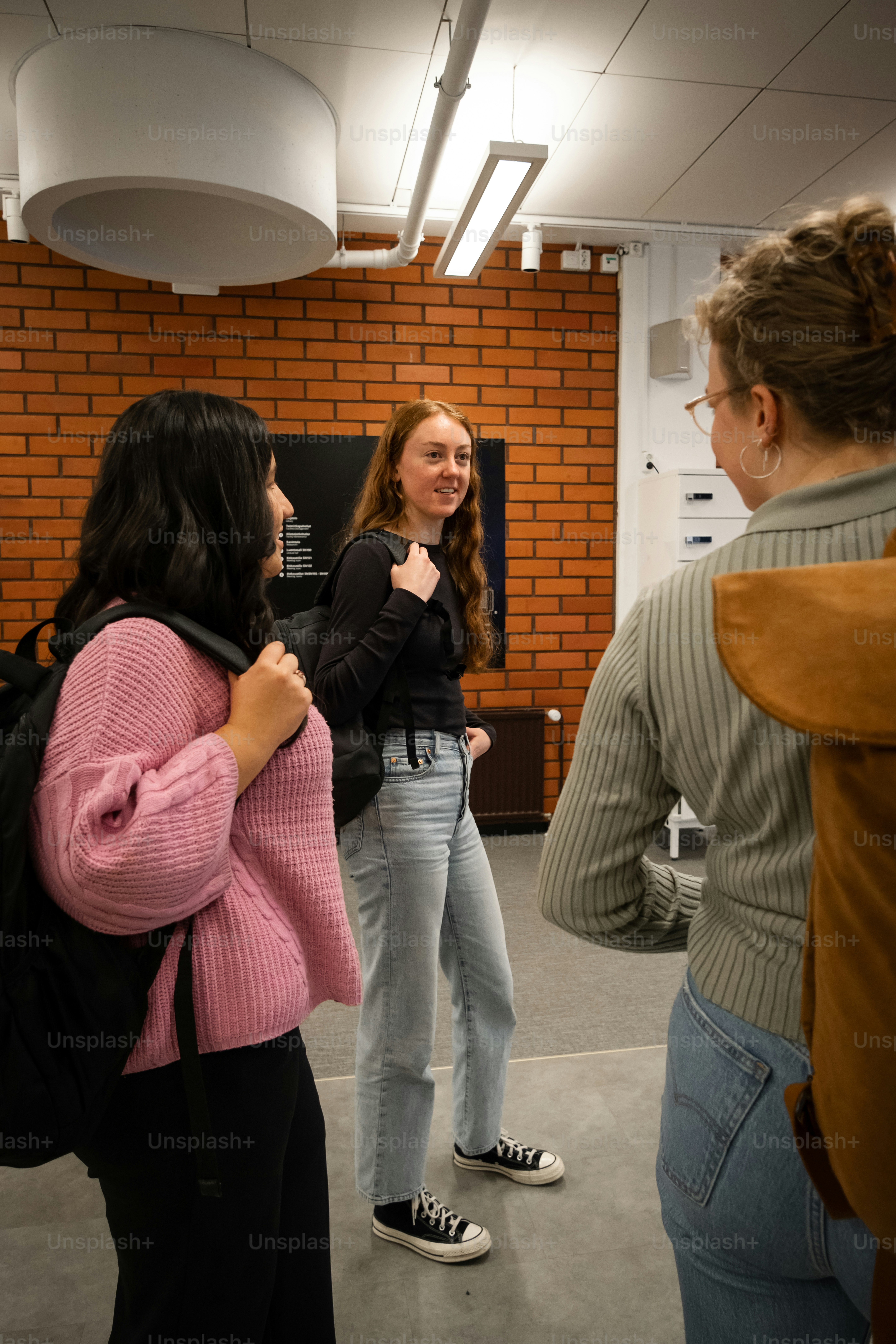 A group of women standing around each other in a room photo – Hanging ...