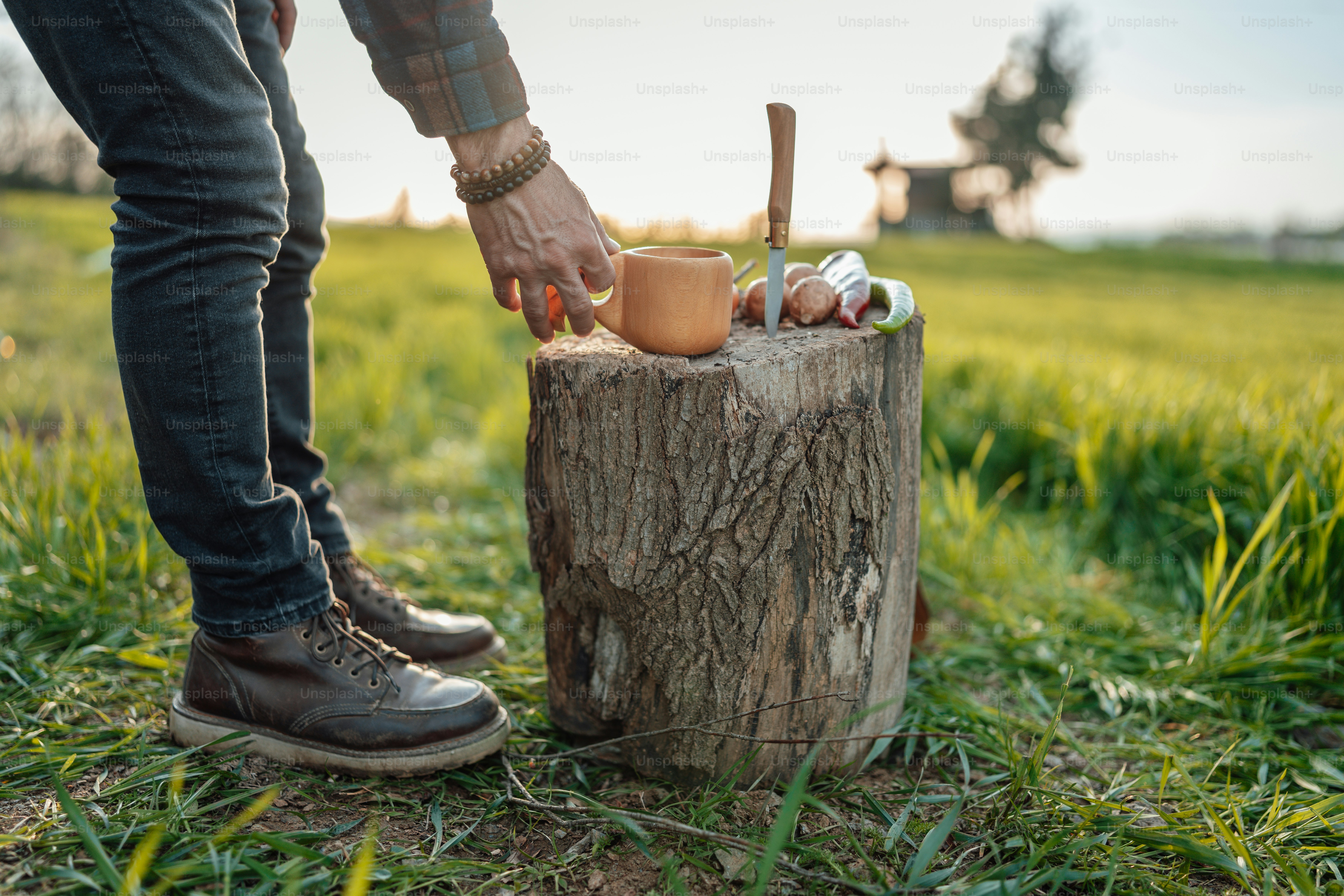 A person standing next to a tree stump holding a cup photo – Travel ...