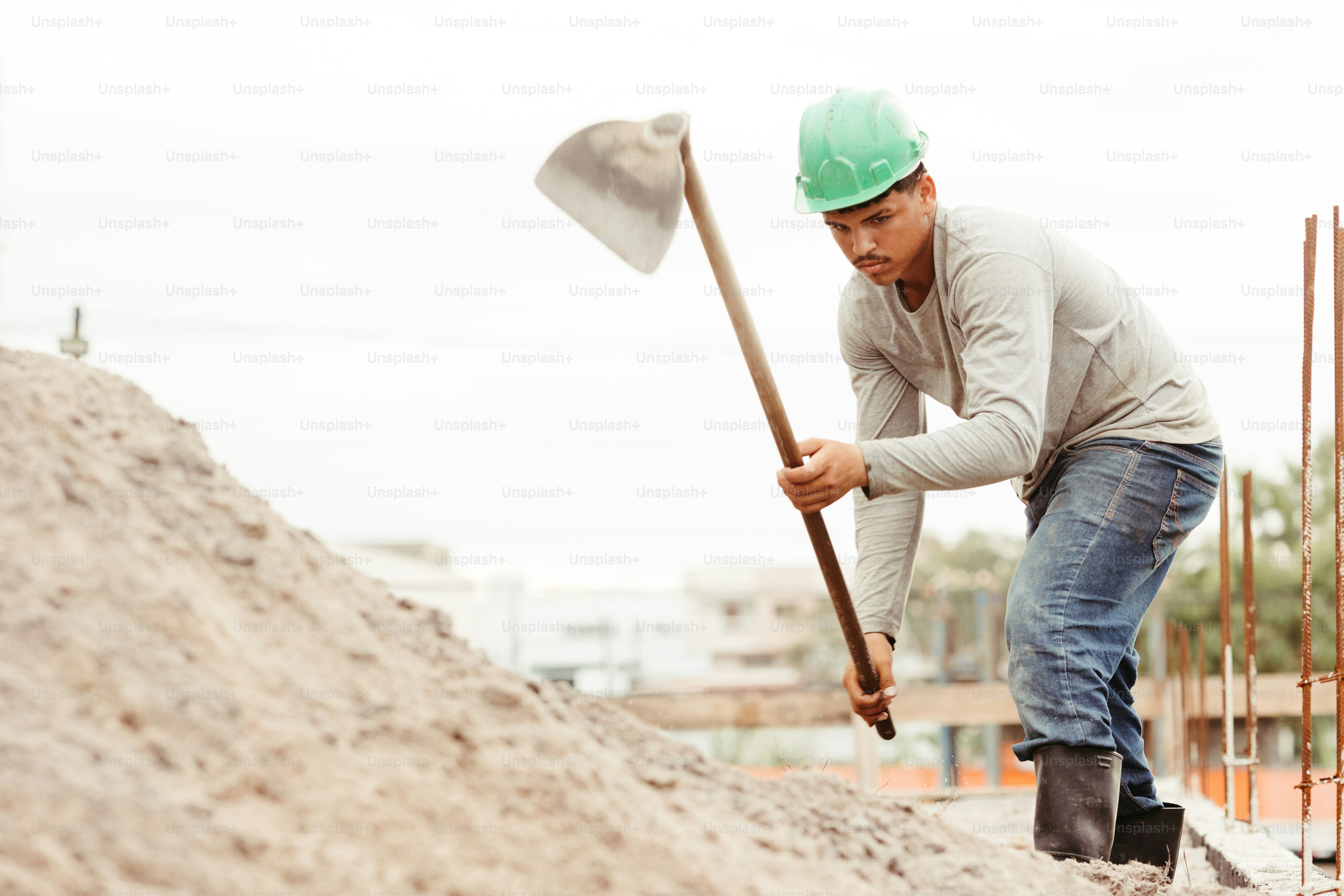A man with a shovel digging in the sand photo – Building worker Image ...