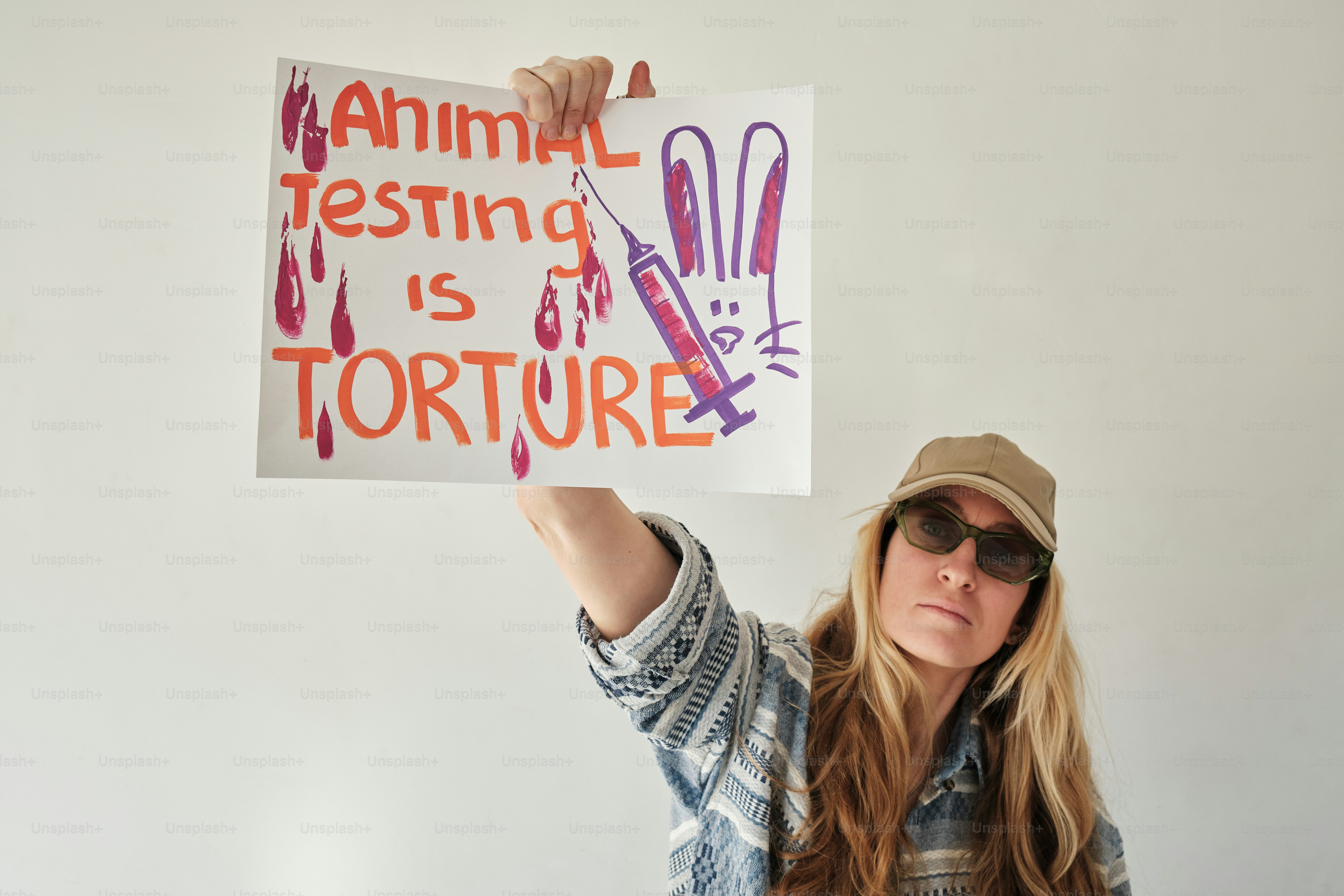 A woman holding a sign that says animal testing is torture photo ...