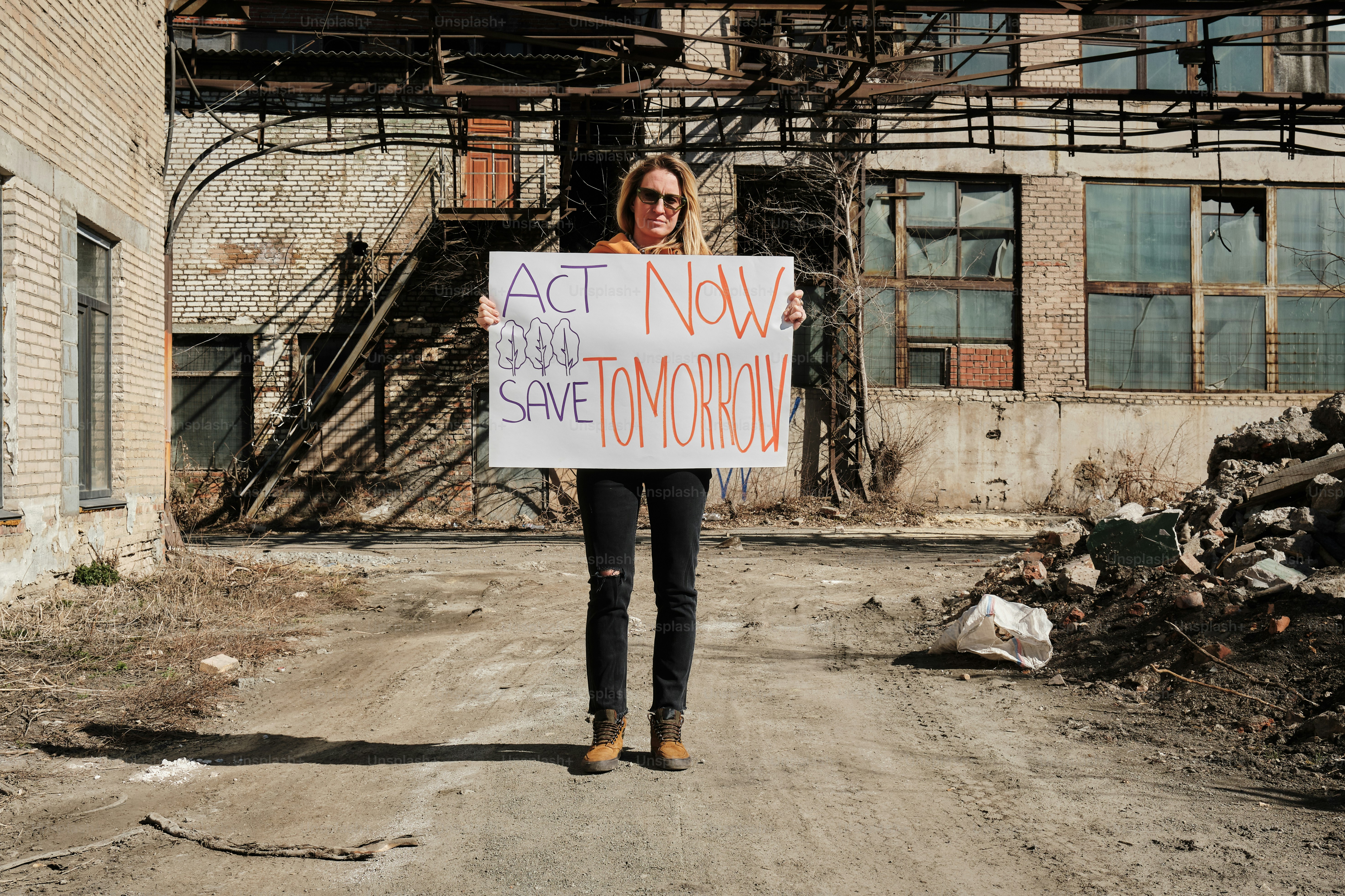 A woman holding a sign that says act now save tomorrow photo – Protest ...
