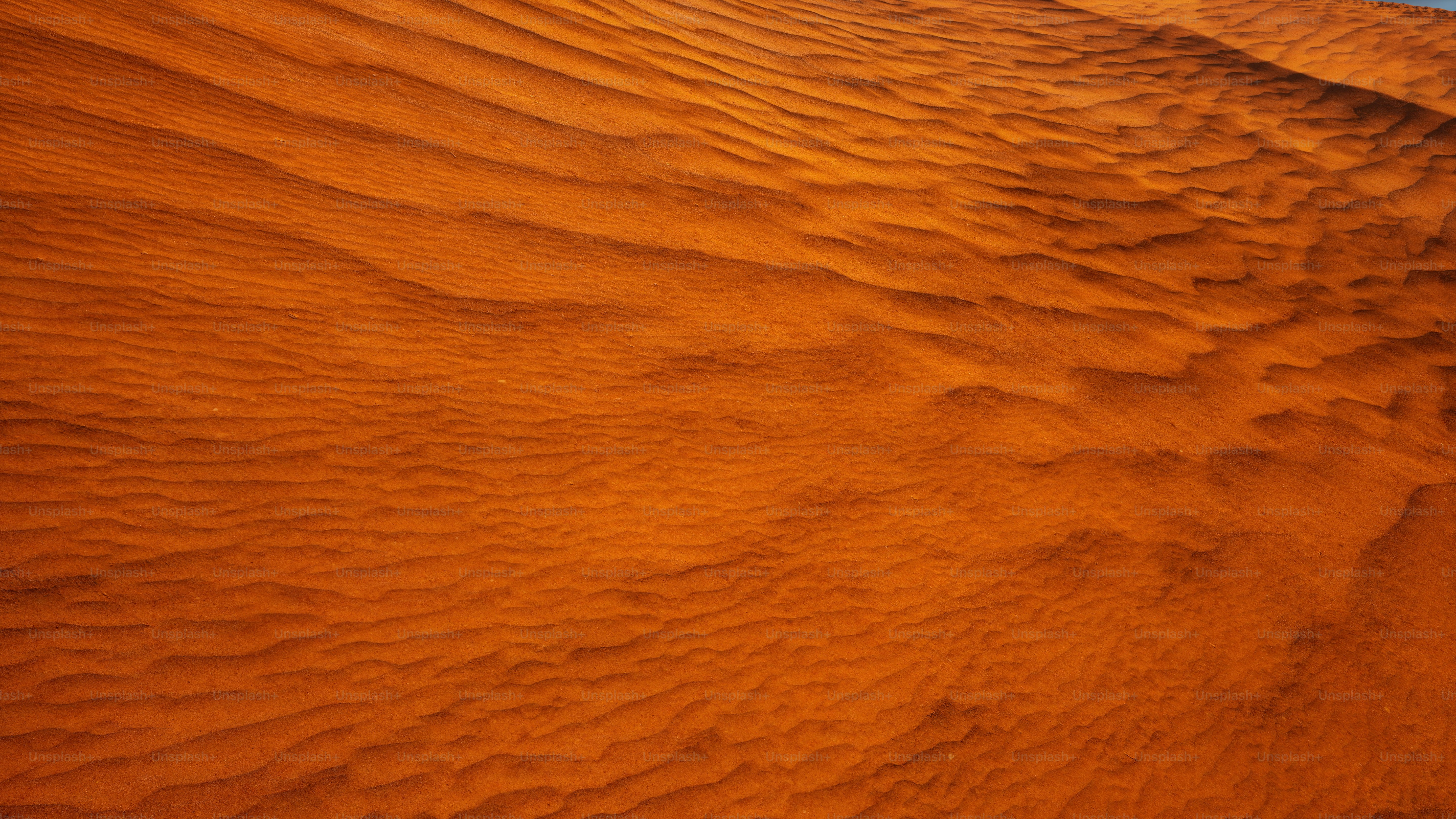 An orange desert with a blue sky in the background photo – Outdoor ...