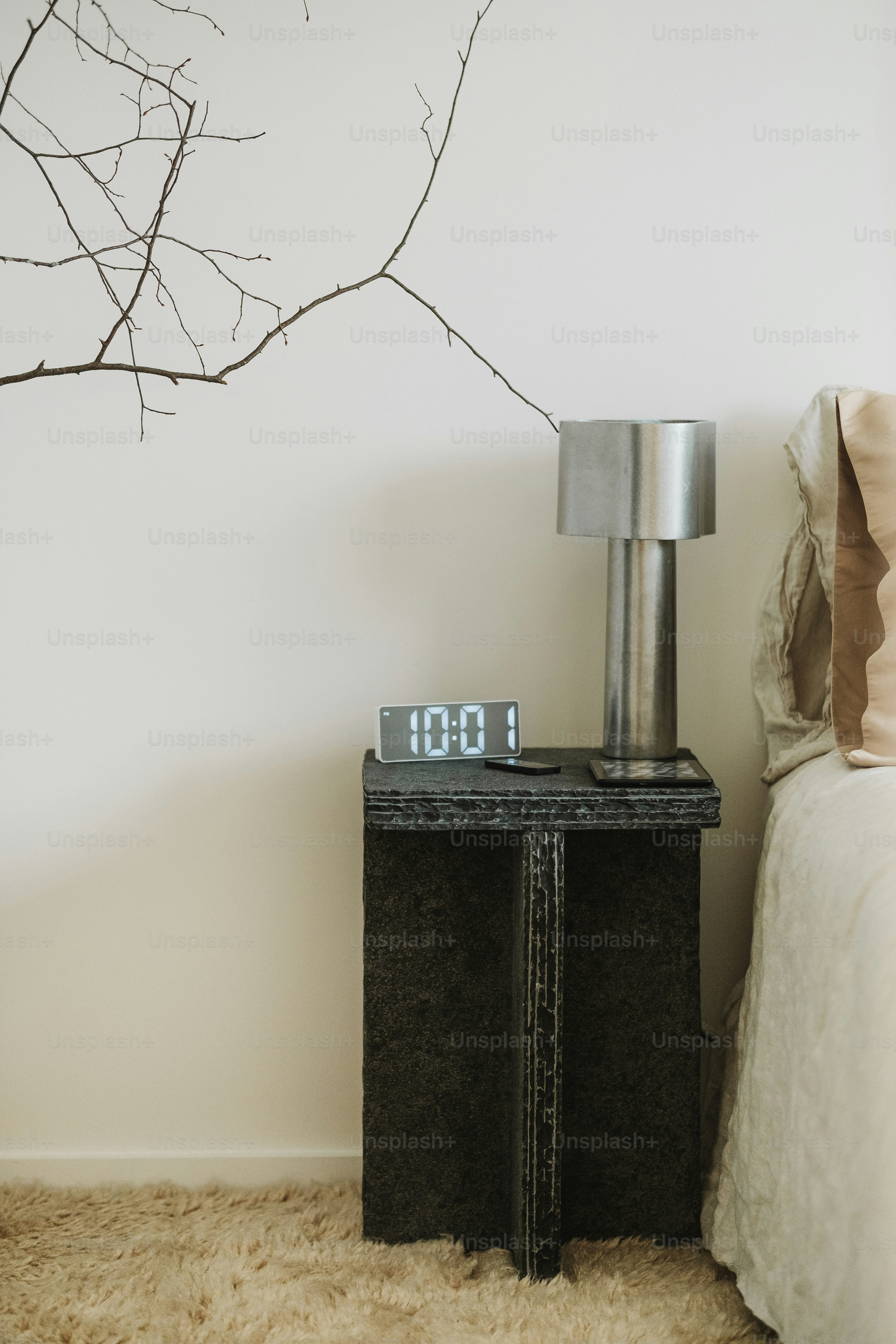 A clock sitting on top of a nightstand next to a bed photo – Decor ...