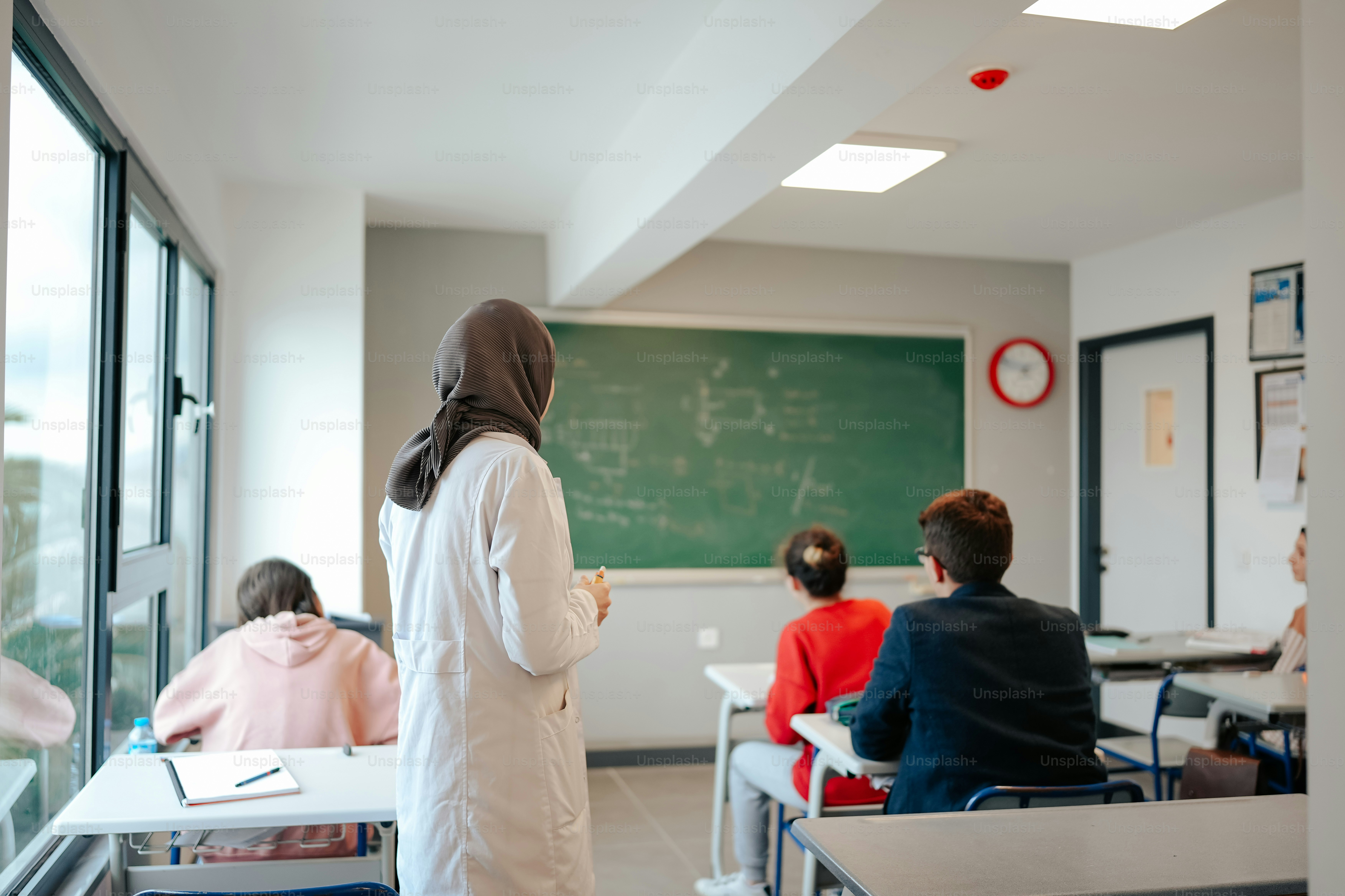 A group of people sitting at desks in front of a blackboard photo ...