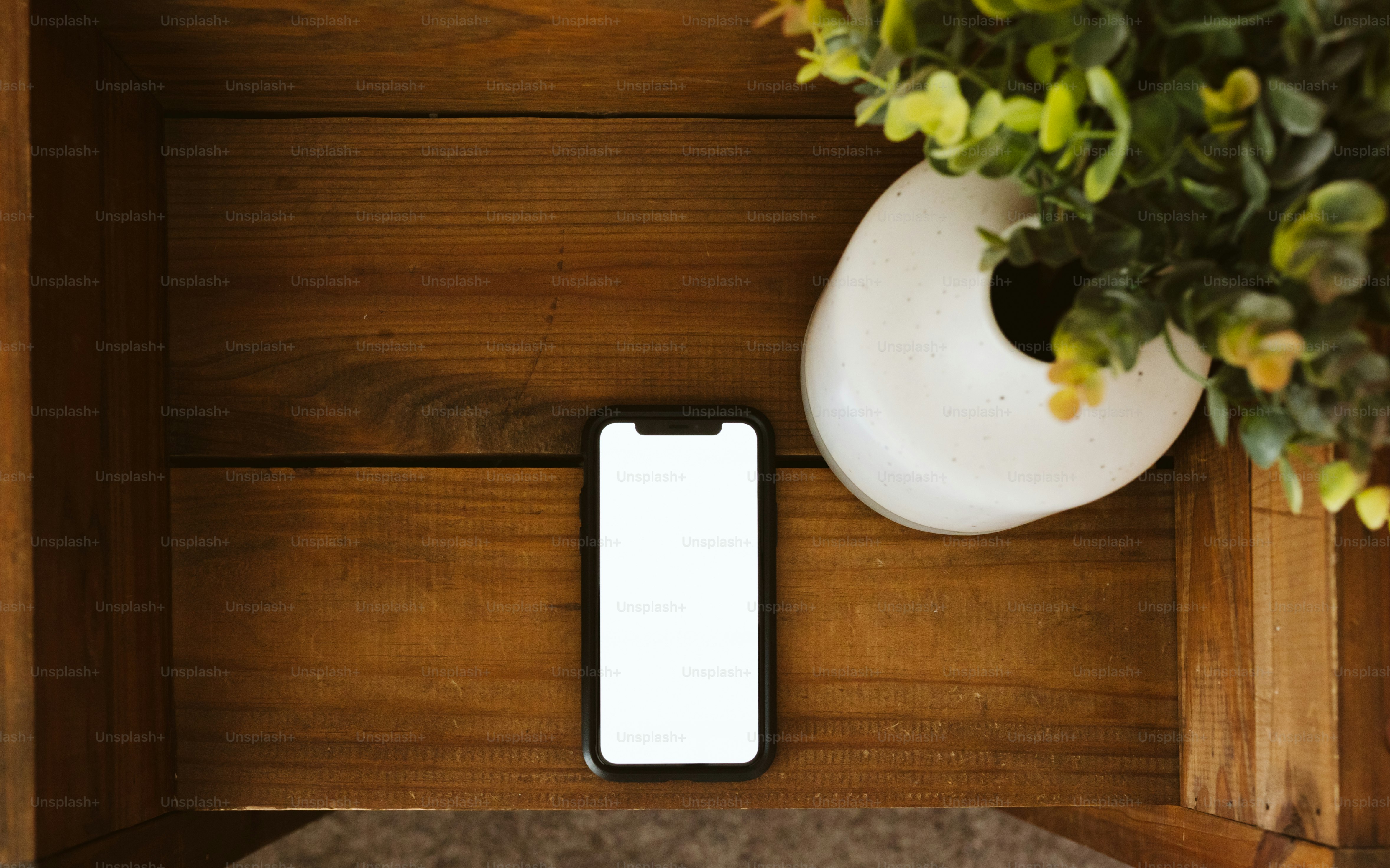 A cell phone sitting on top of a wooden table photo – Phone Image on ...