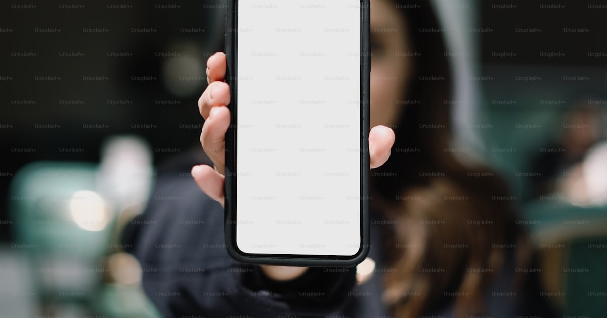 白い画面のスマートフォンを掲げる女性の写真 携帯電話 Unsplashの写真