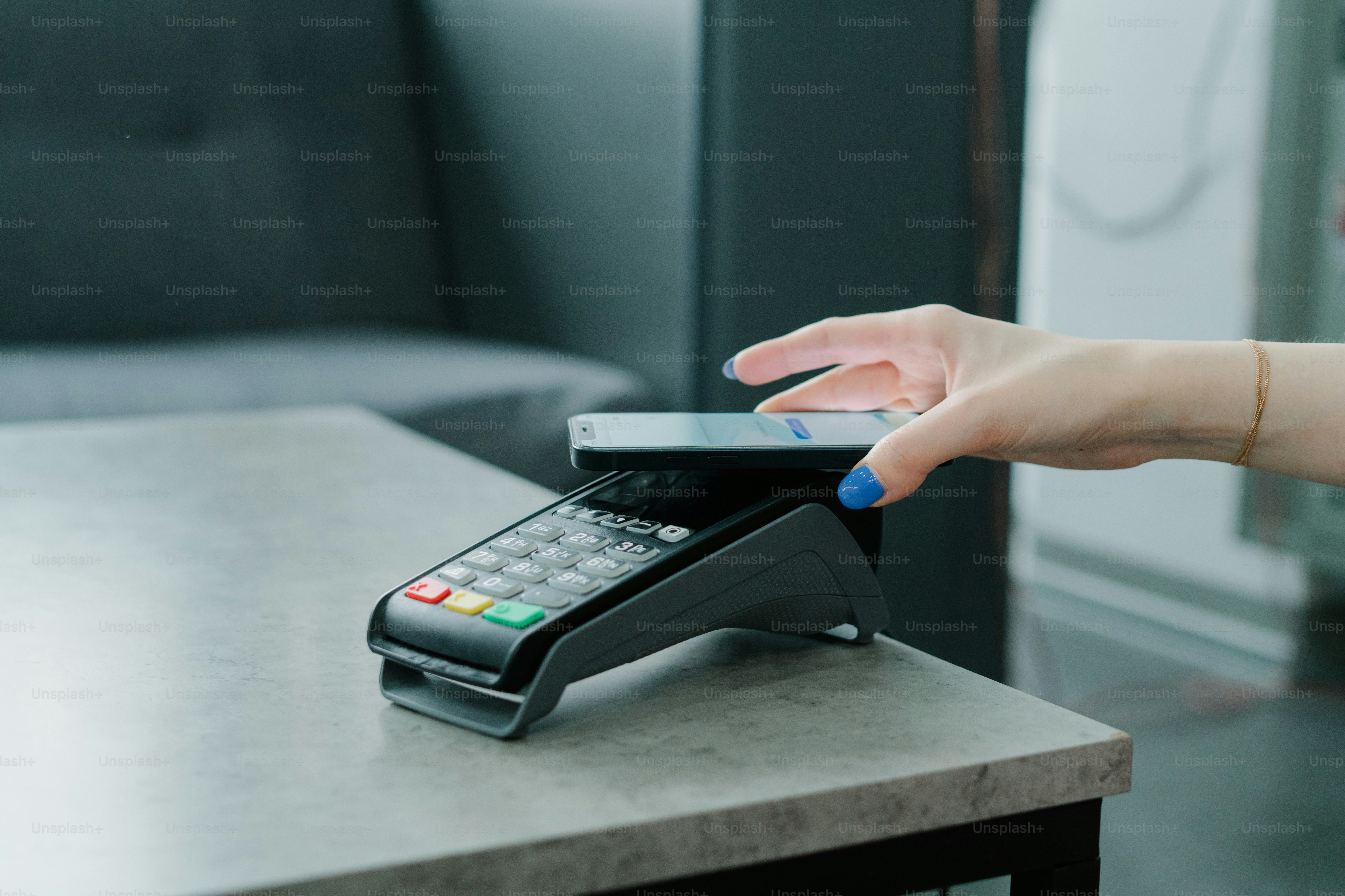 A woman's hand holding a cell phone over a cash register photo ...