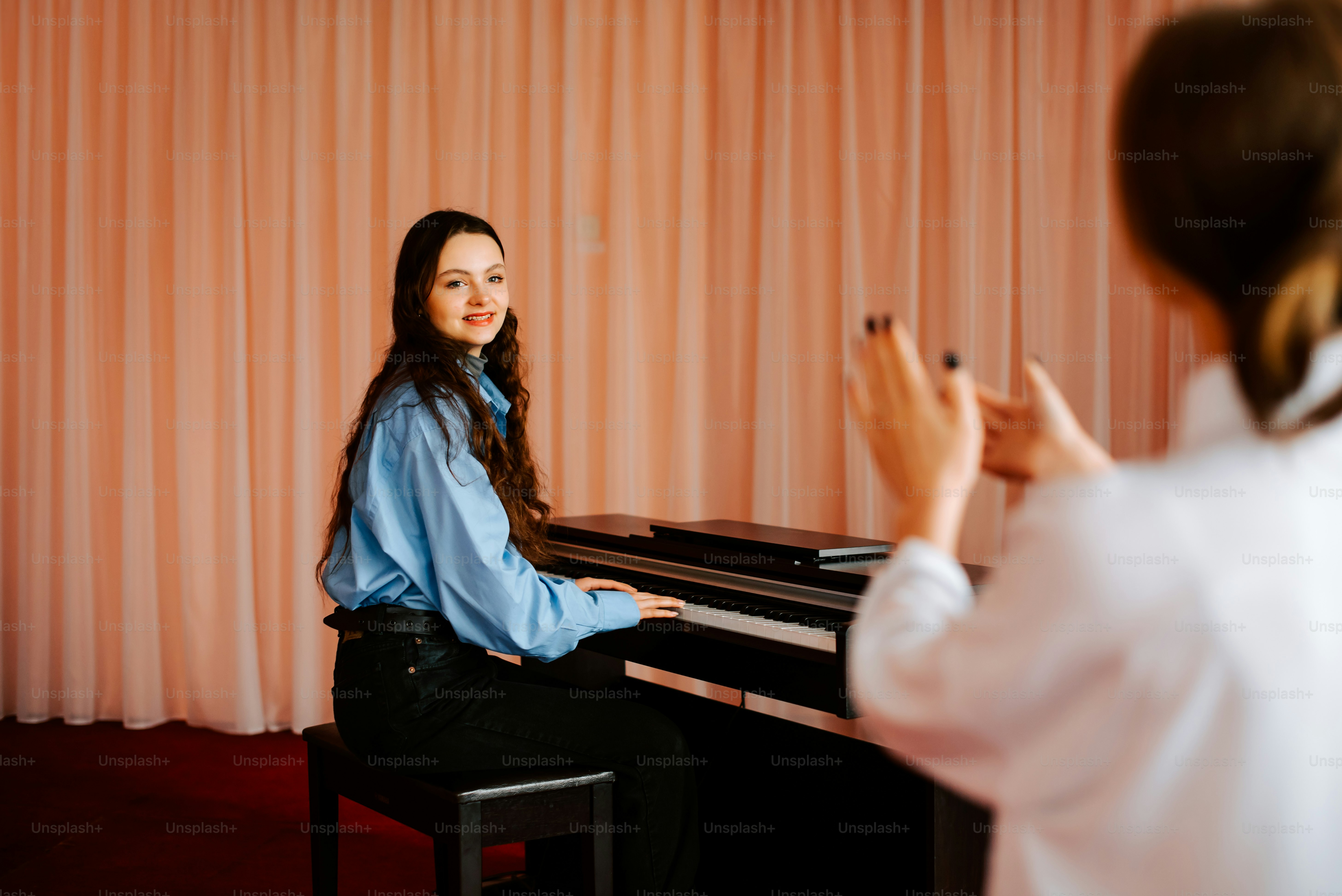 A woman sitting at a piano playing a song photo – Music teach Image on ...