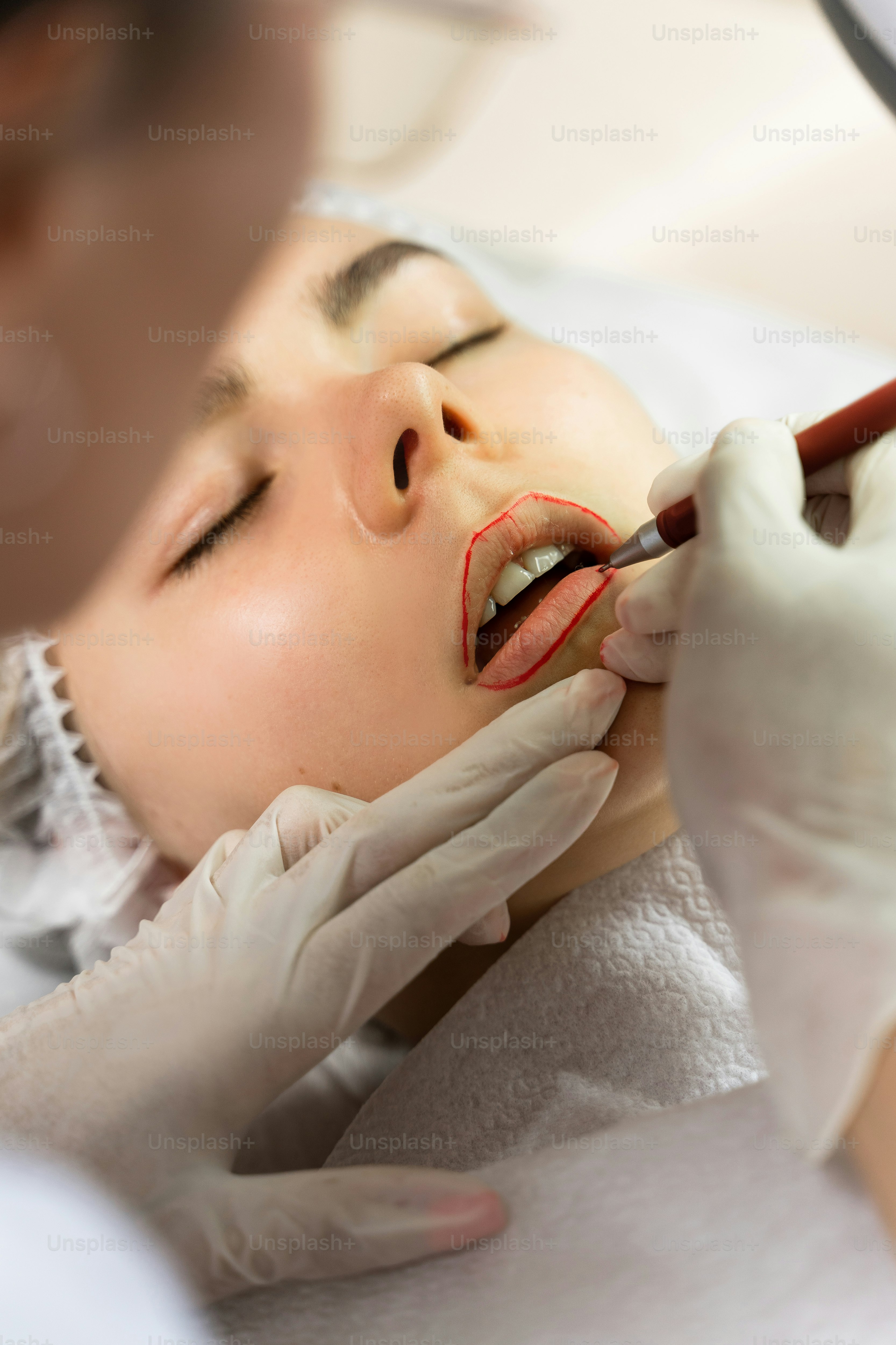 Professional permanent make-up artist and her client during lip ...