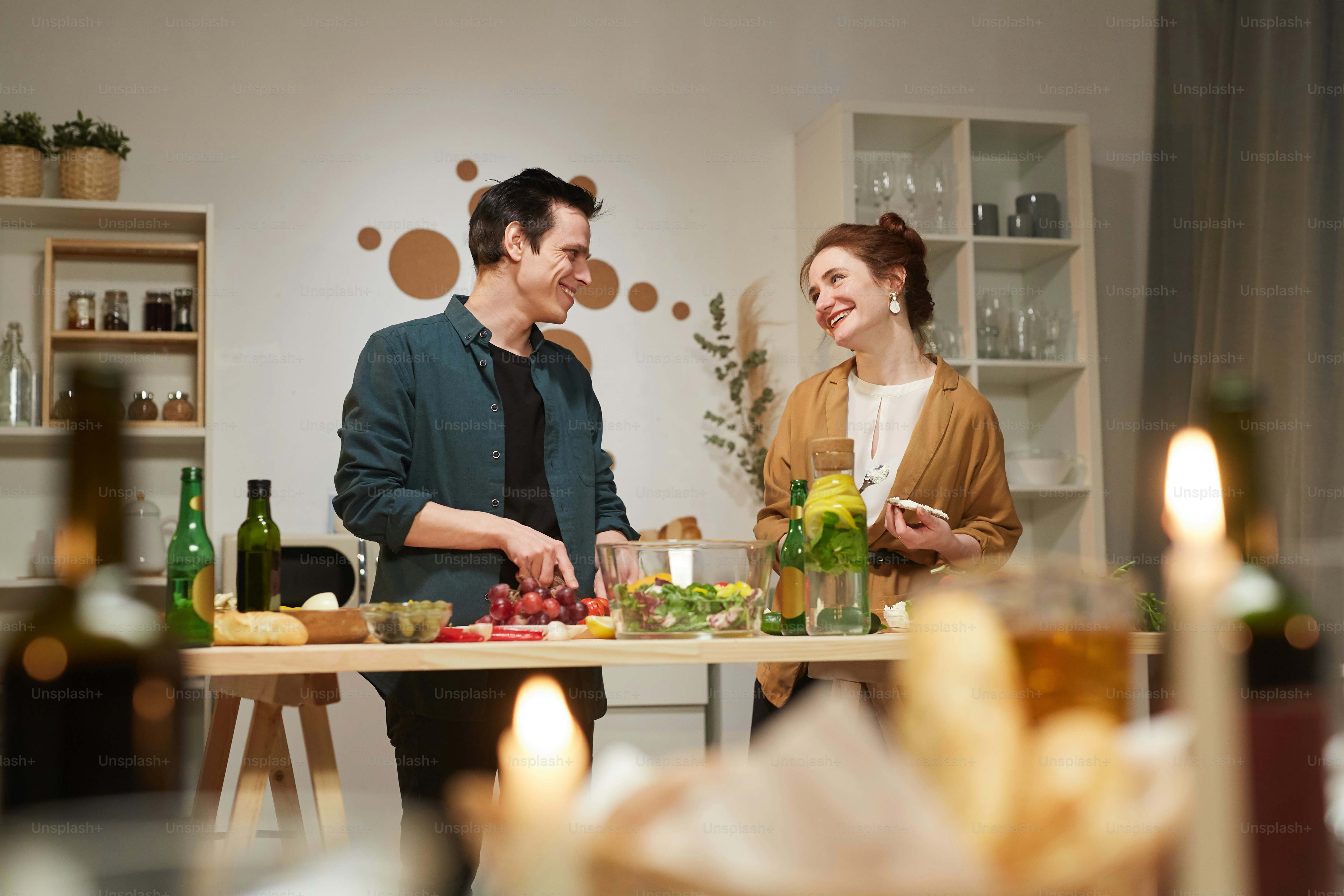 Young couple smiling to each other while cooking dinner together in ...
