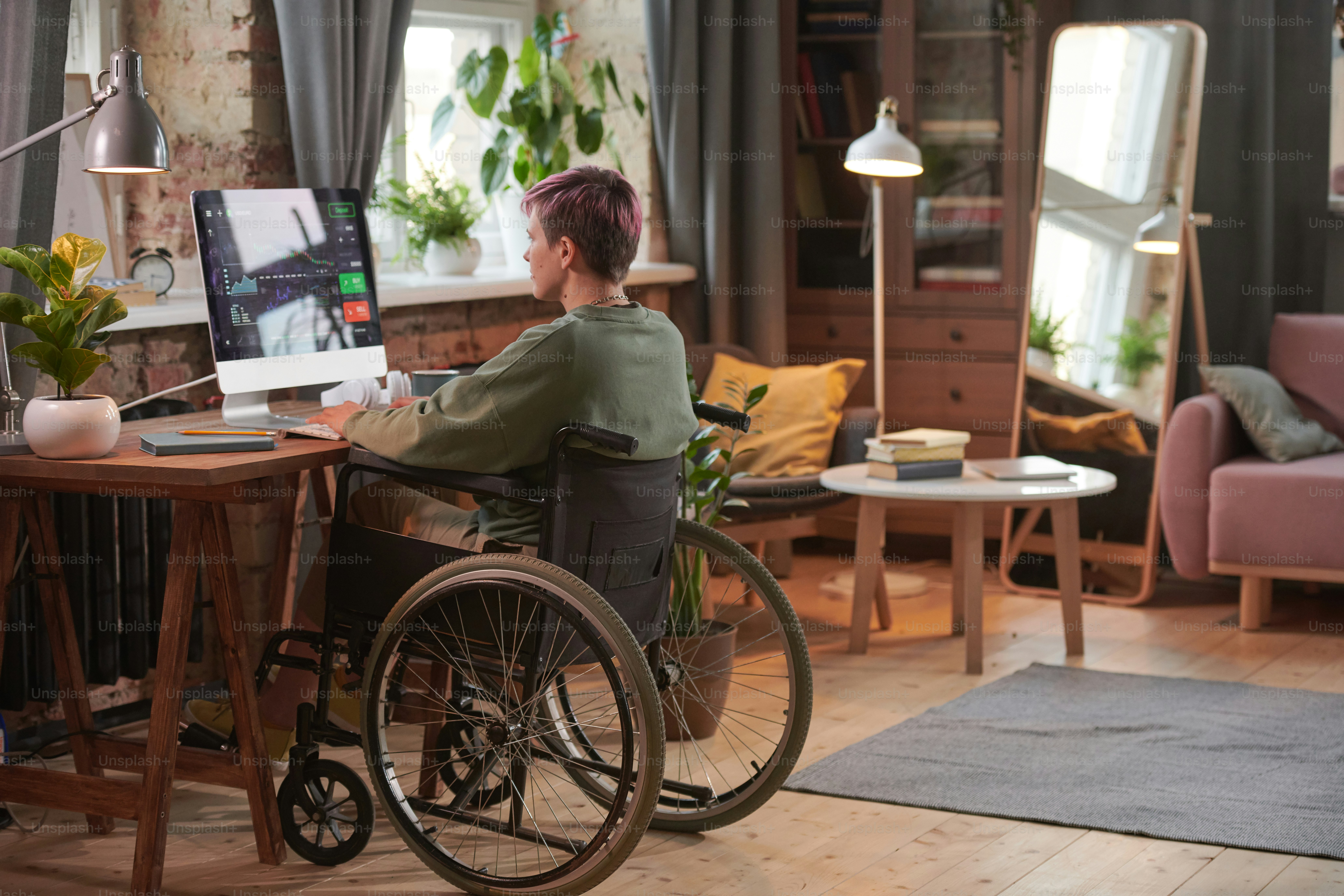 Rear view of disabled woman working as a programmer on computer with ...
